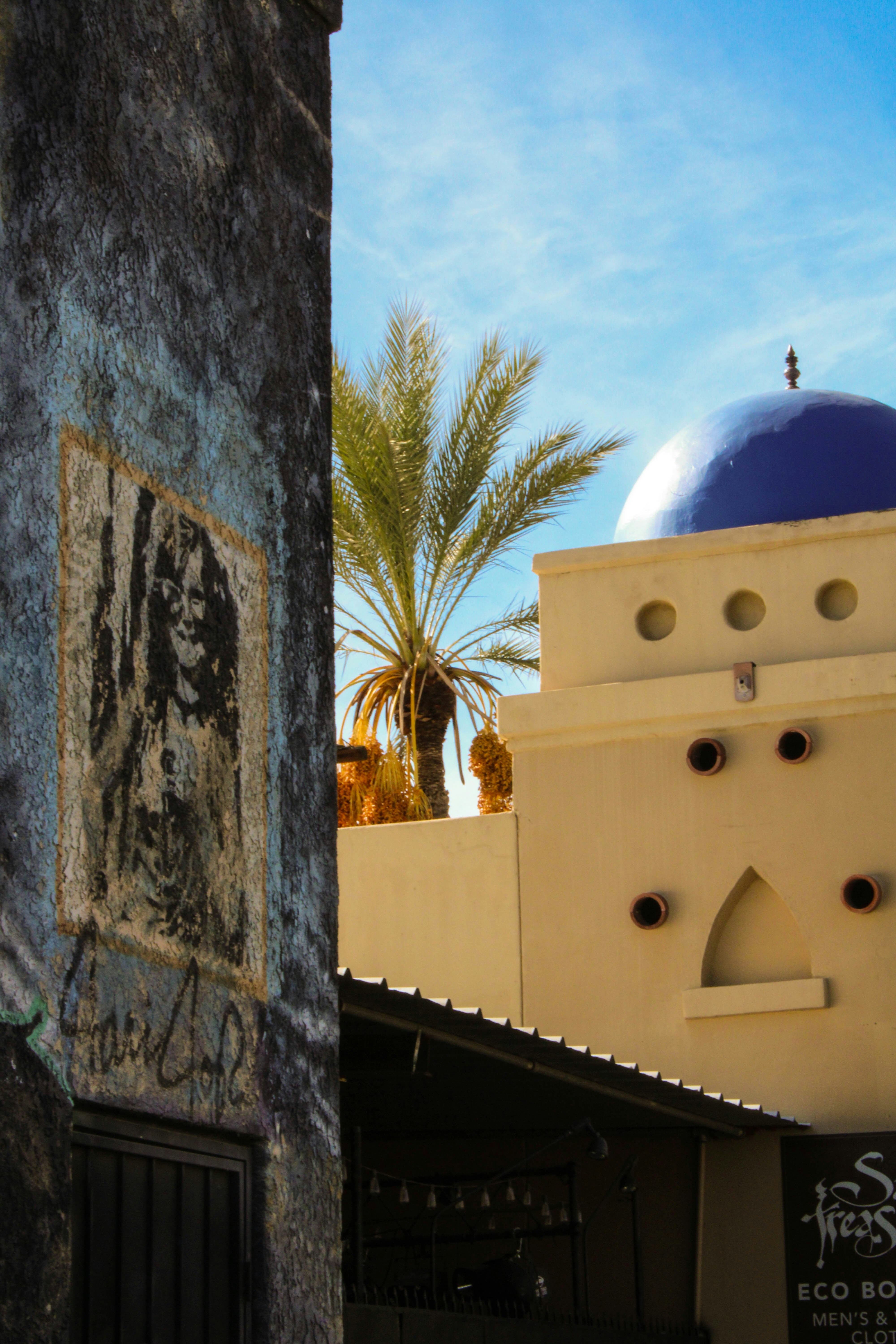 Azure Dome Over a Sunlit Med Street: Palm Fronds and Weathered Walls