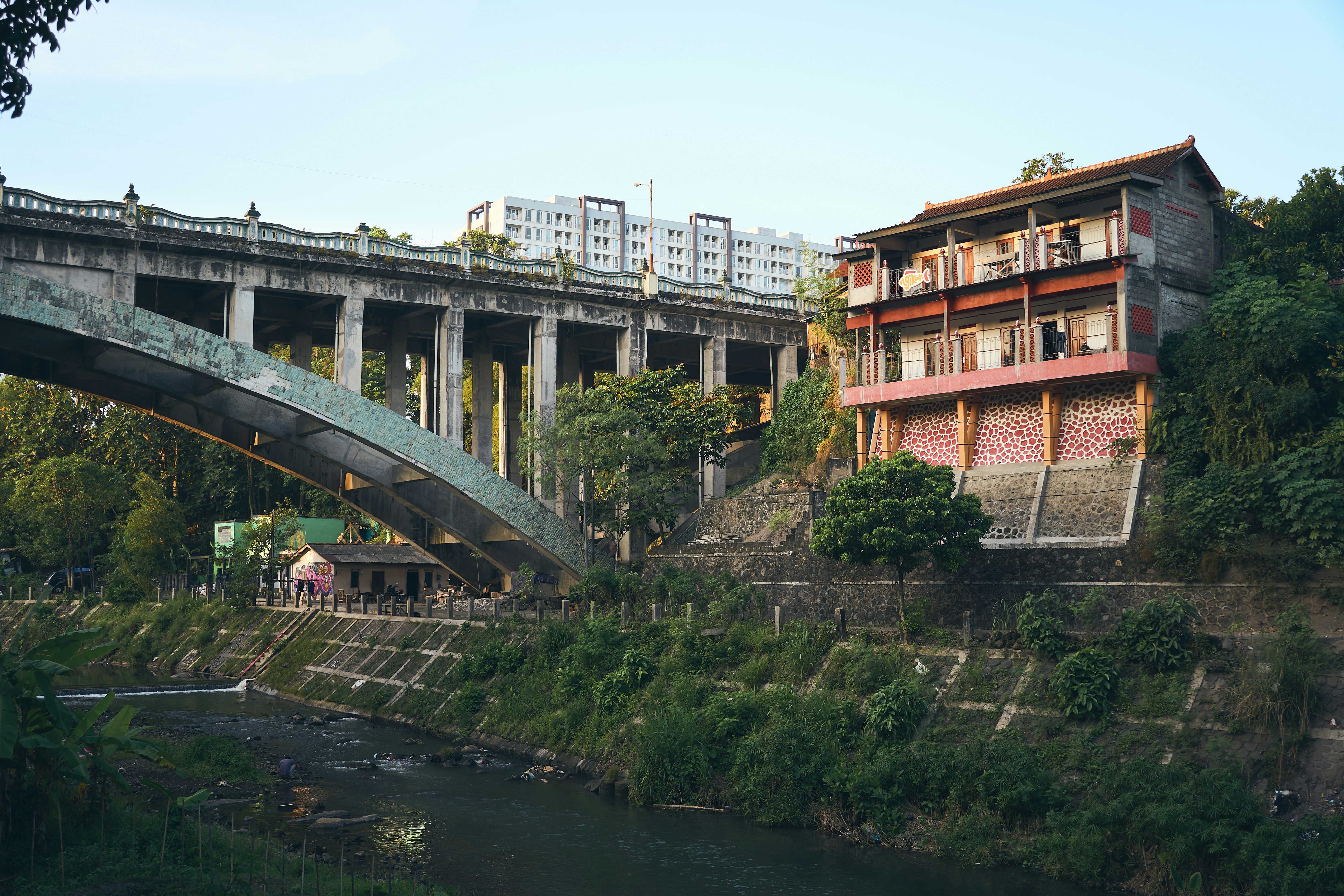 Arch and Riverside: The Bridge Framing a Red-Brick House by the Quiet River