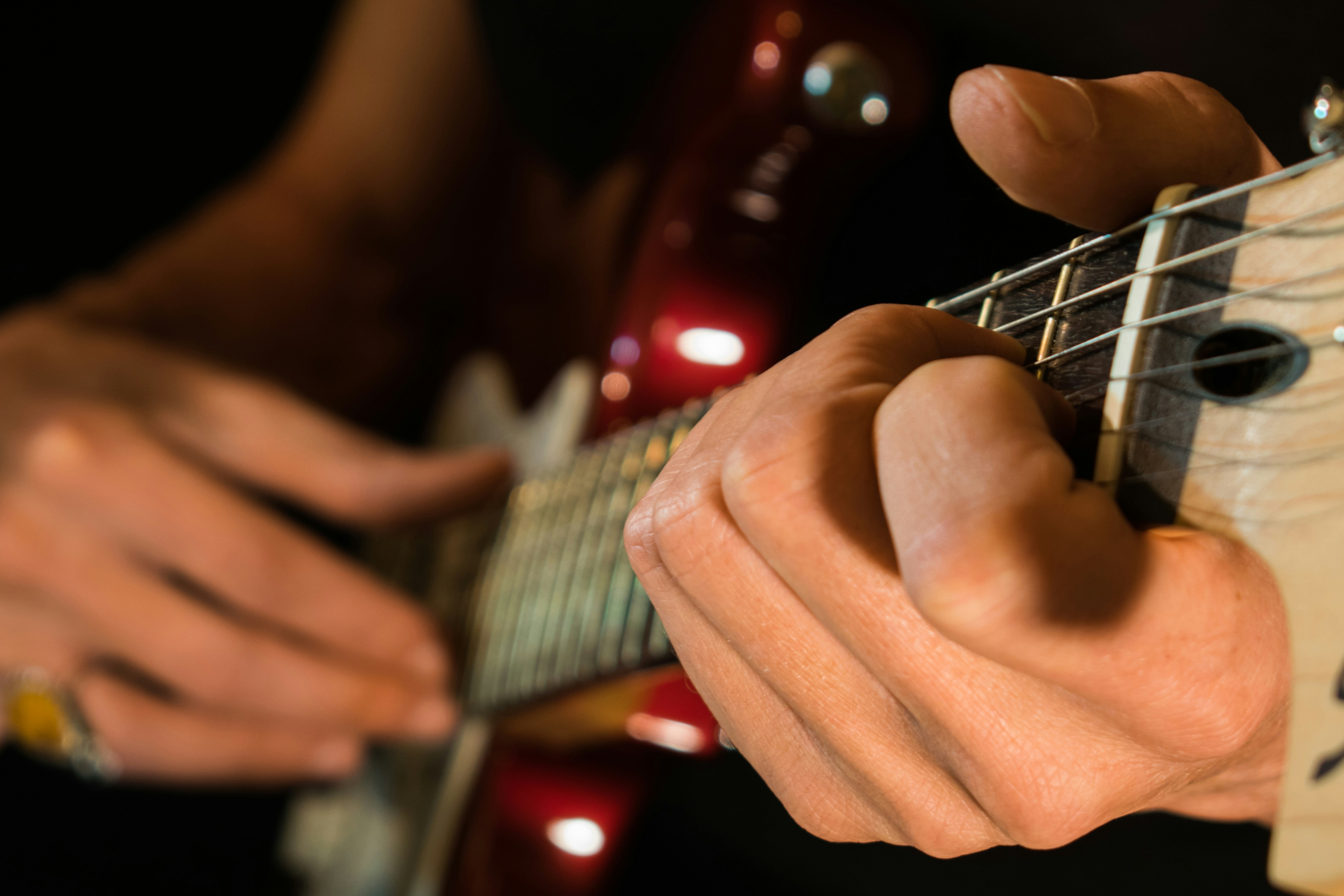 Close-up of hands skillfully playing a guitar, highlighting the intricate finger placement and the instrument's details.