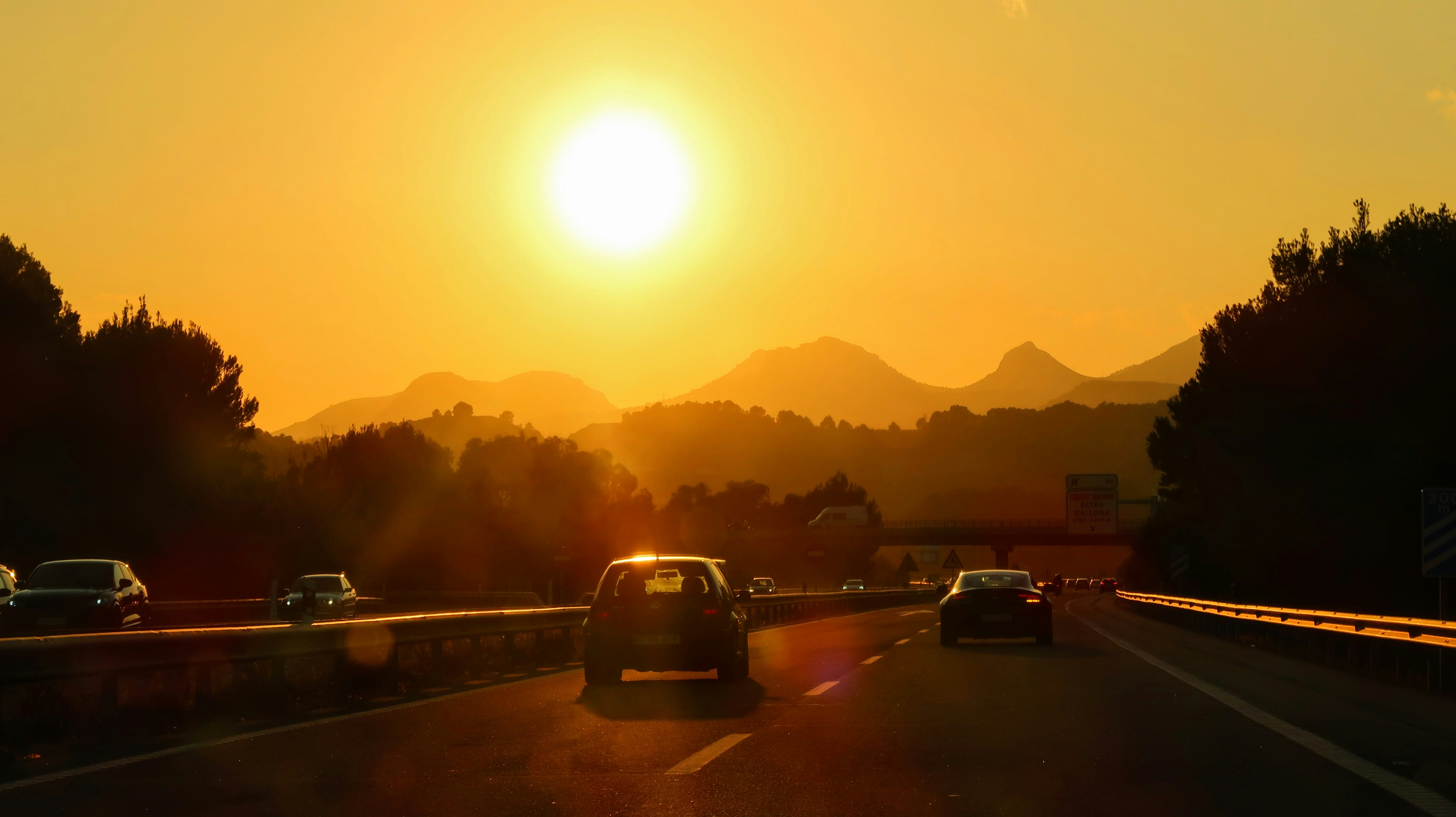 Sunlit Highway at Dusk: Golden Orbs, Long Shadows, and Distant Peaks