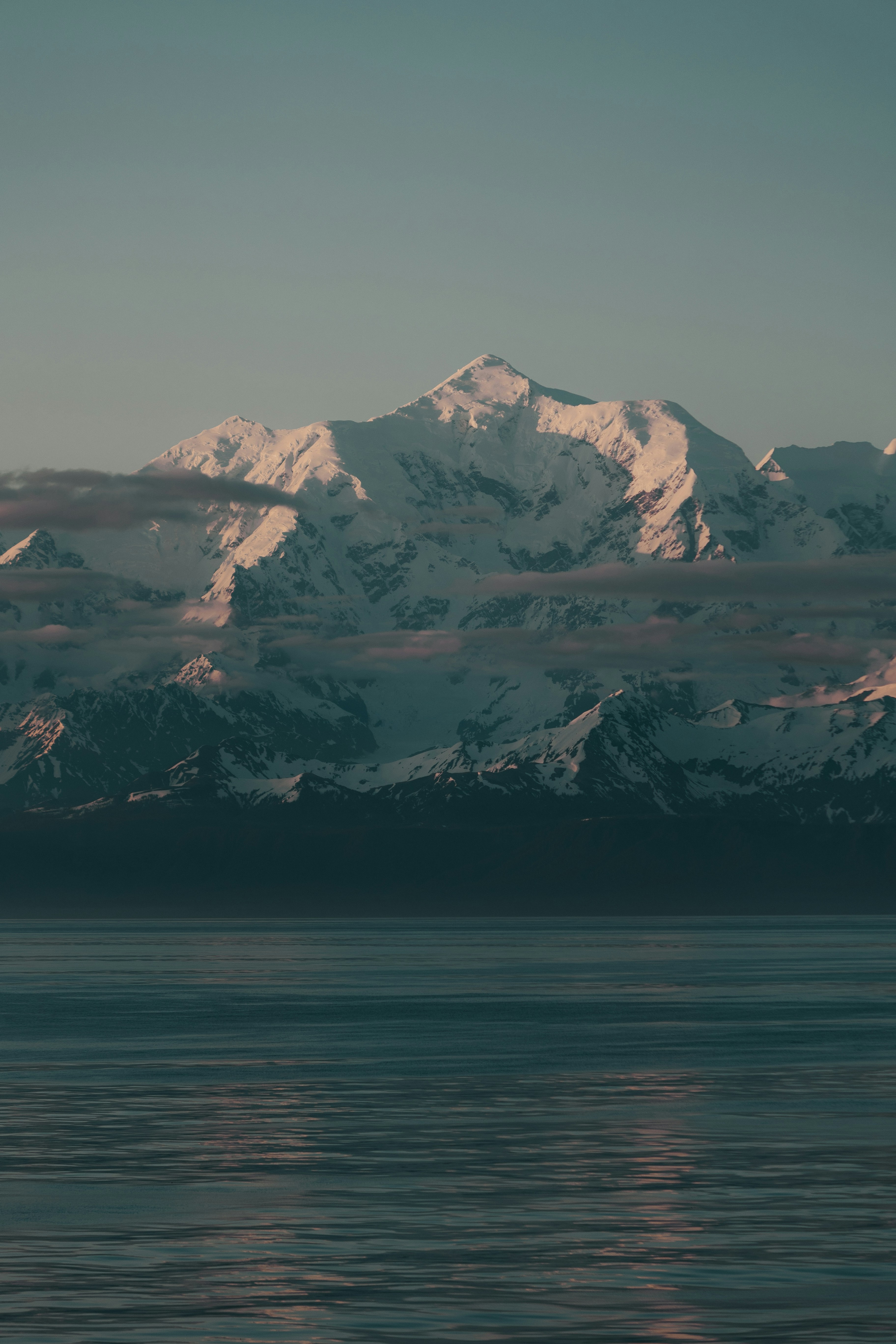 a large mountain covered in snow next to a body of water