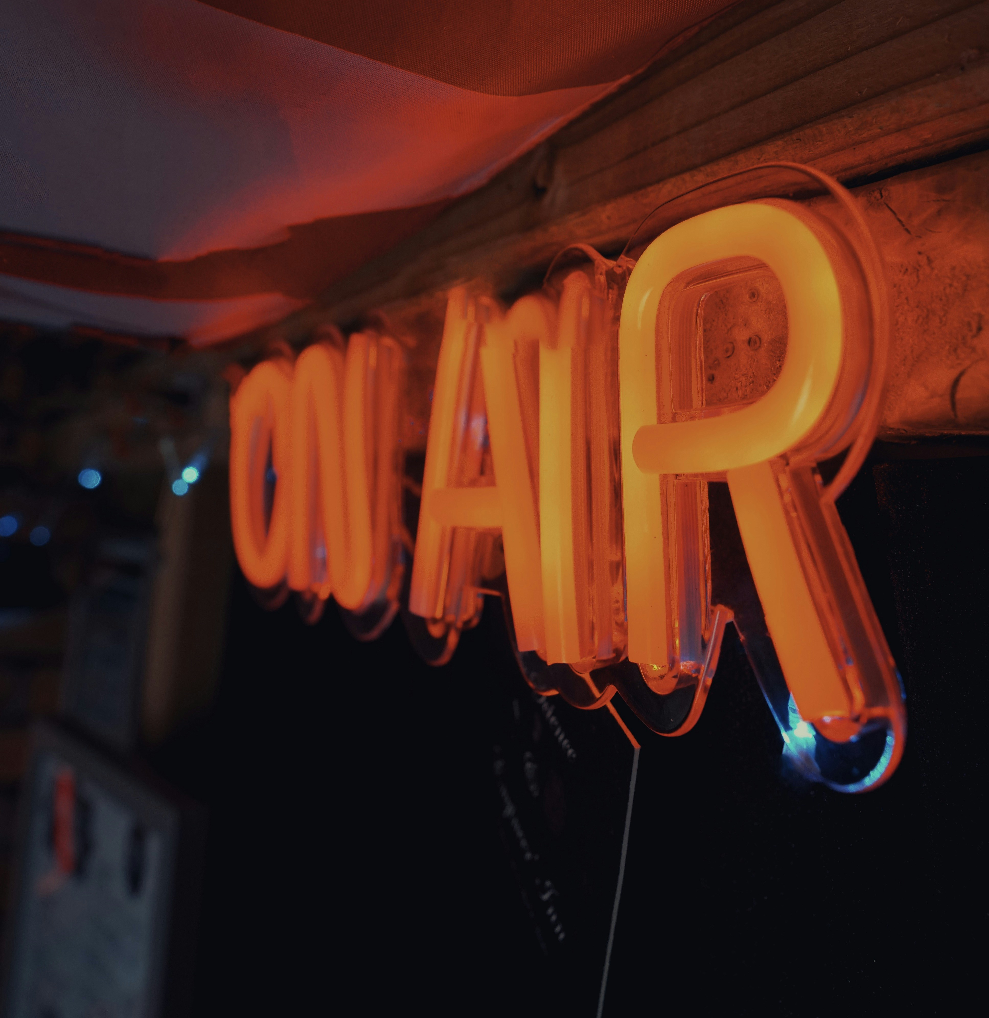Neon sign reading 'ON AIR' glows in warm orange tones, set against a dark background. The vibrant lettering captures the essence of live broadcasting.