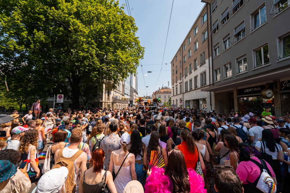 Una folla di persone che camminano lungo una strada accanto a edifici ... Una folla di persone che camminano lungo una strada accanto a edifici ...