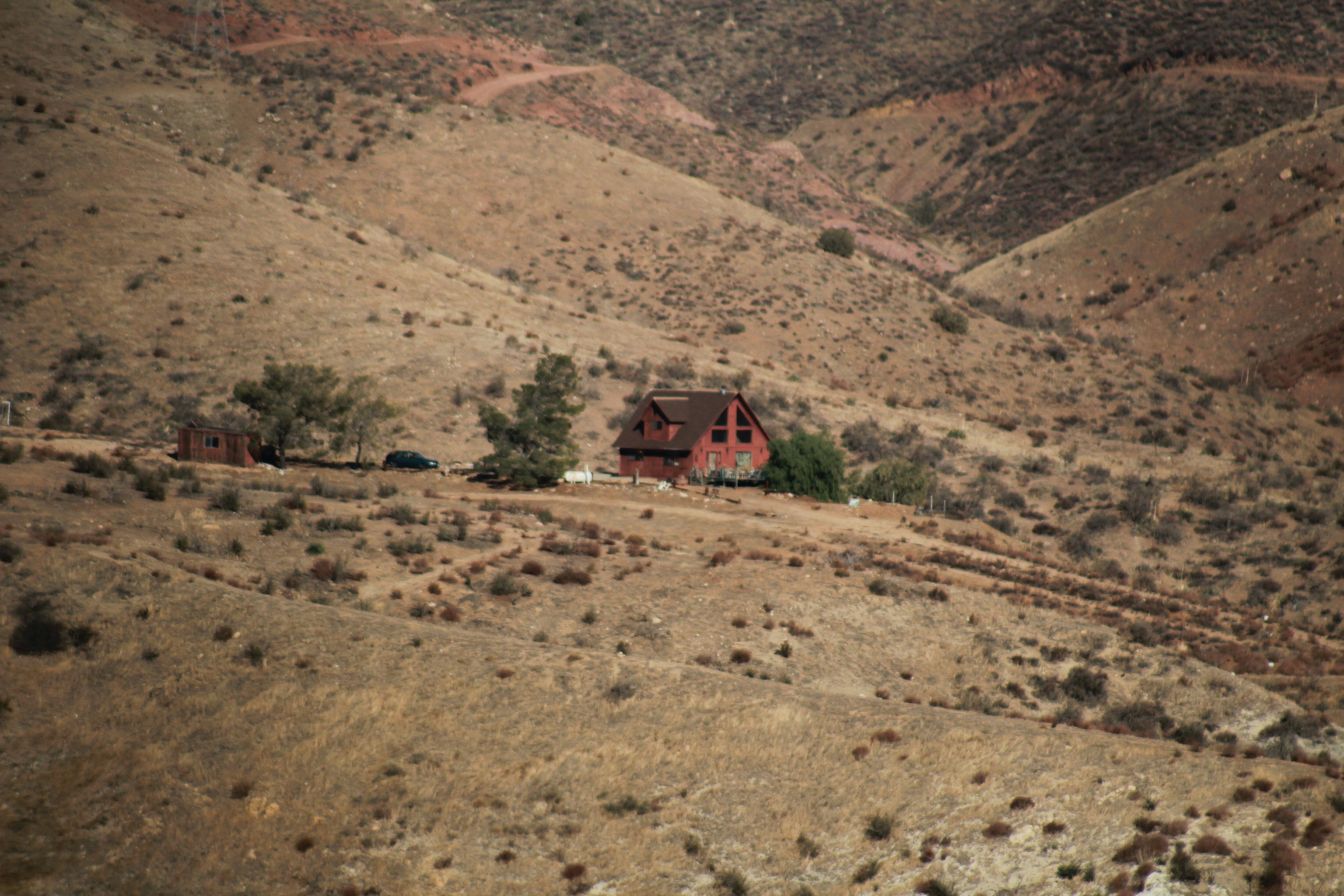 red house in the mountains | a house in the middle of a hilly area