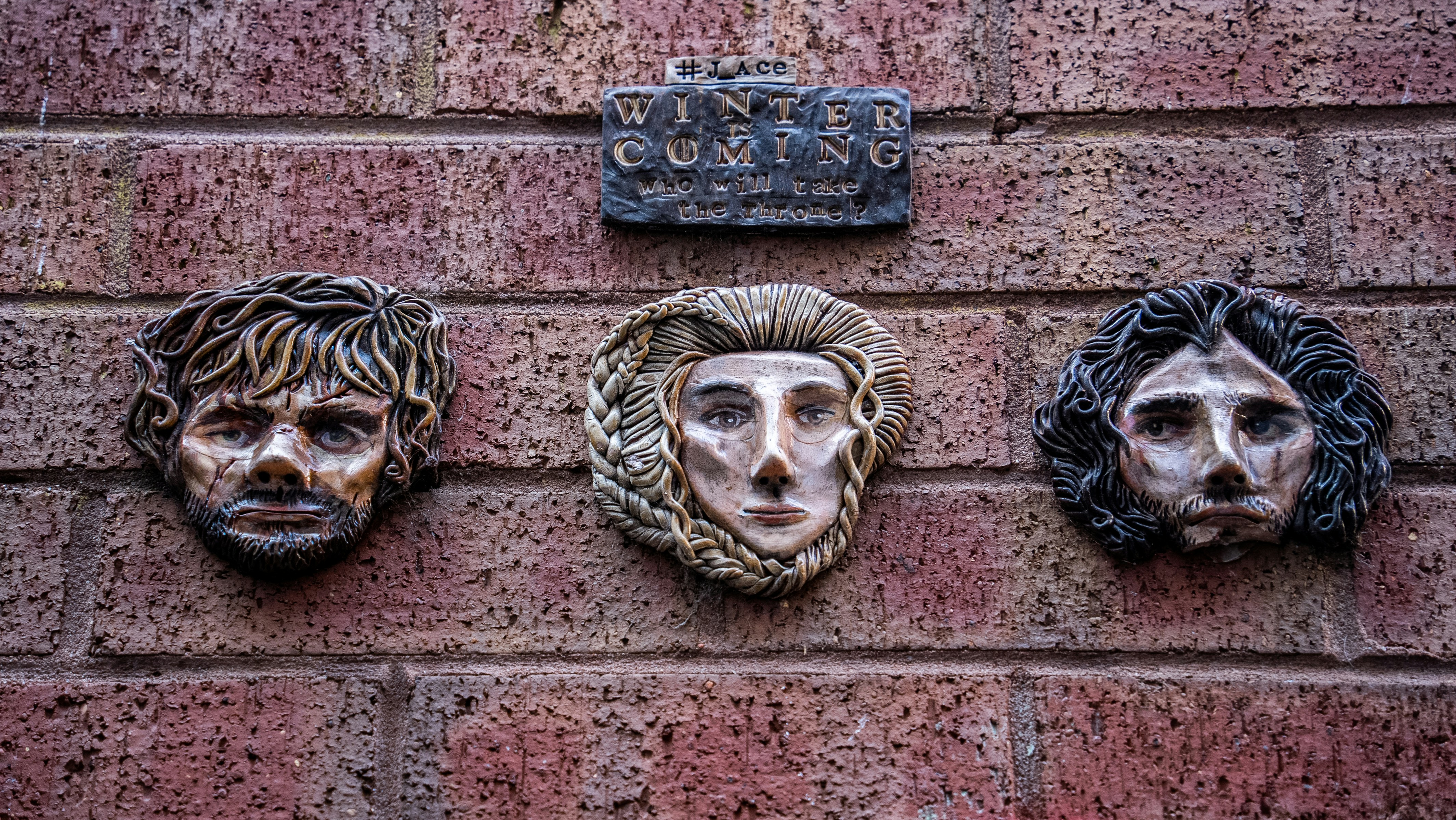 A brick wall with three metal faces on it photo – Free Belfast Image on ...