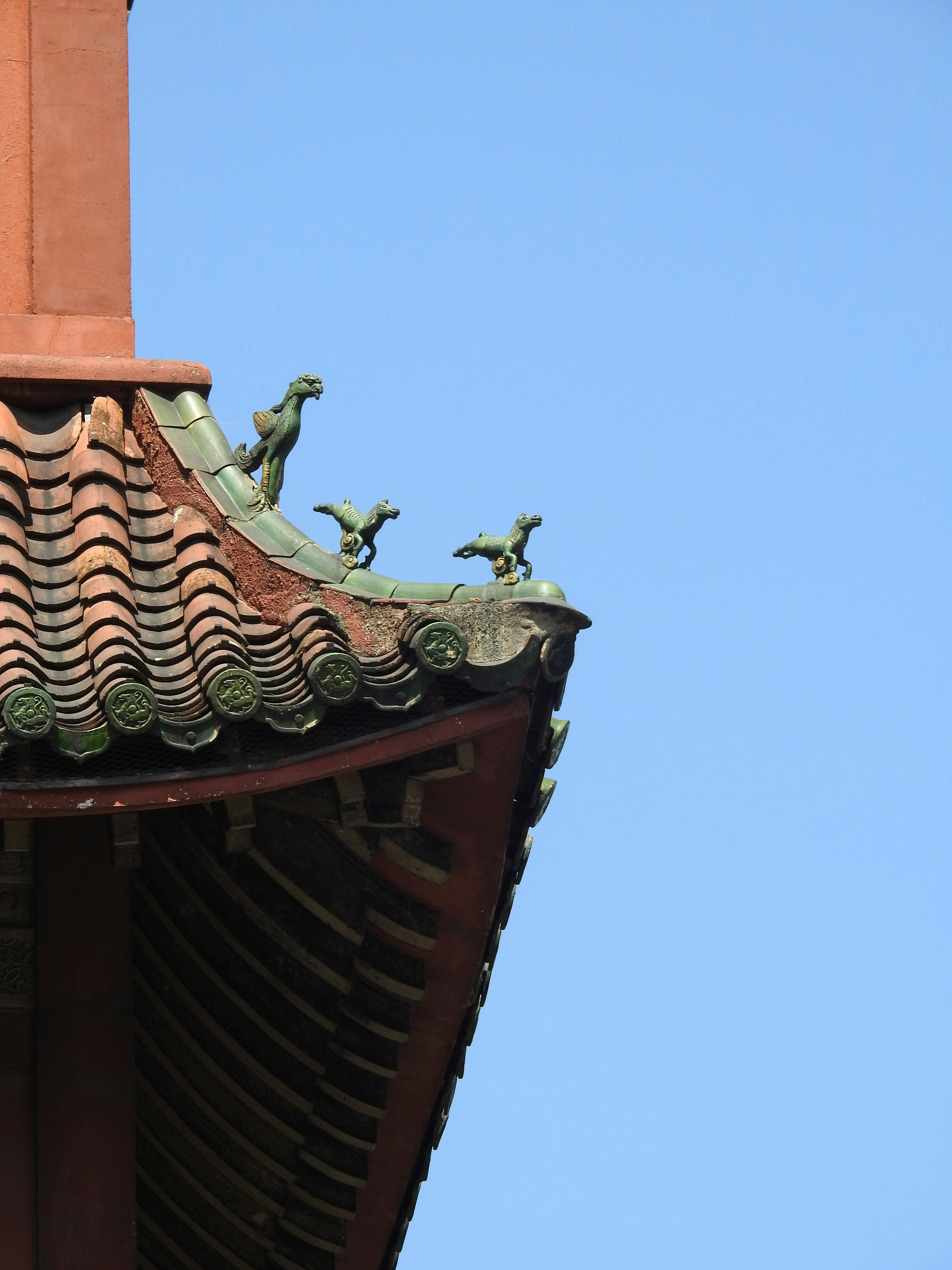 Green-Glazed Dragon Statues Guard a Chinese Roof Ridge Beneath a Clear Blue Sky