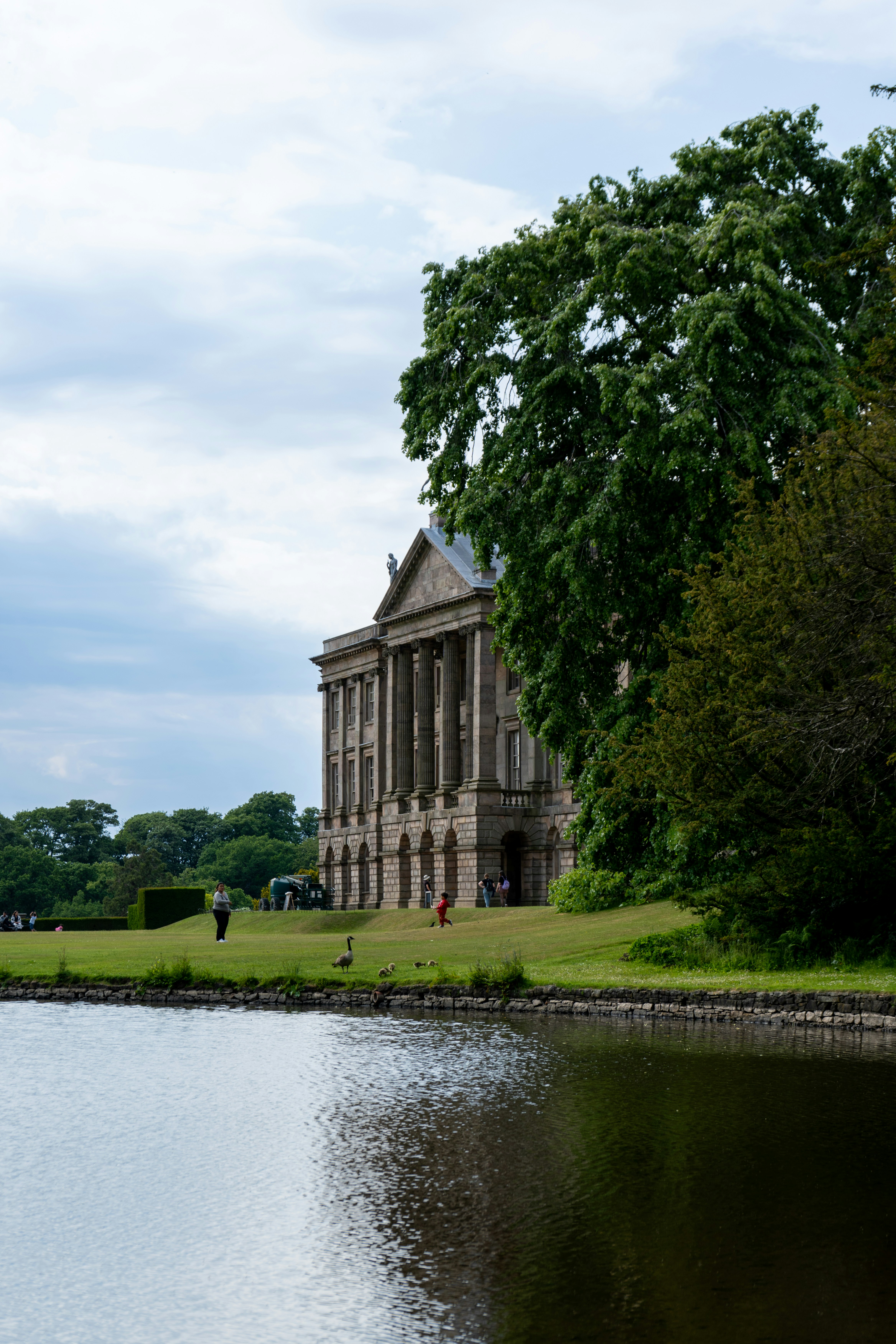Stone Colonnade by the Lake, Framed by a Lush Riverside Tree