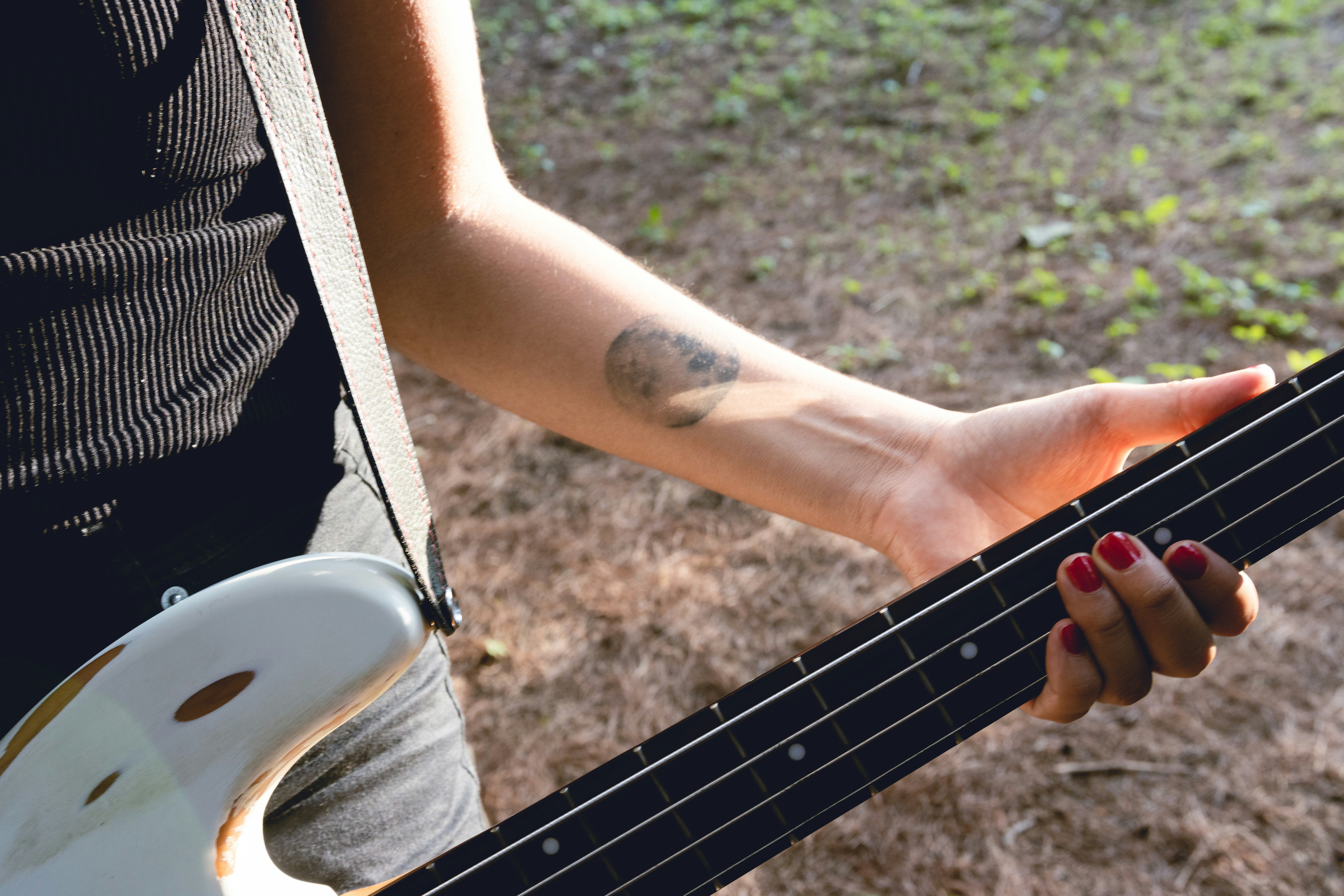Fretboard in Focus: A Bassist's Hand Anchoring a White Bass Guitar