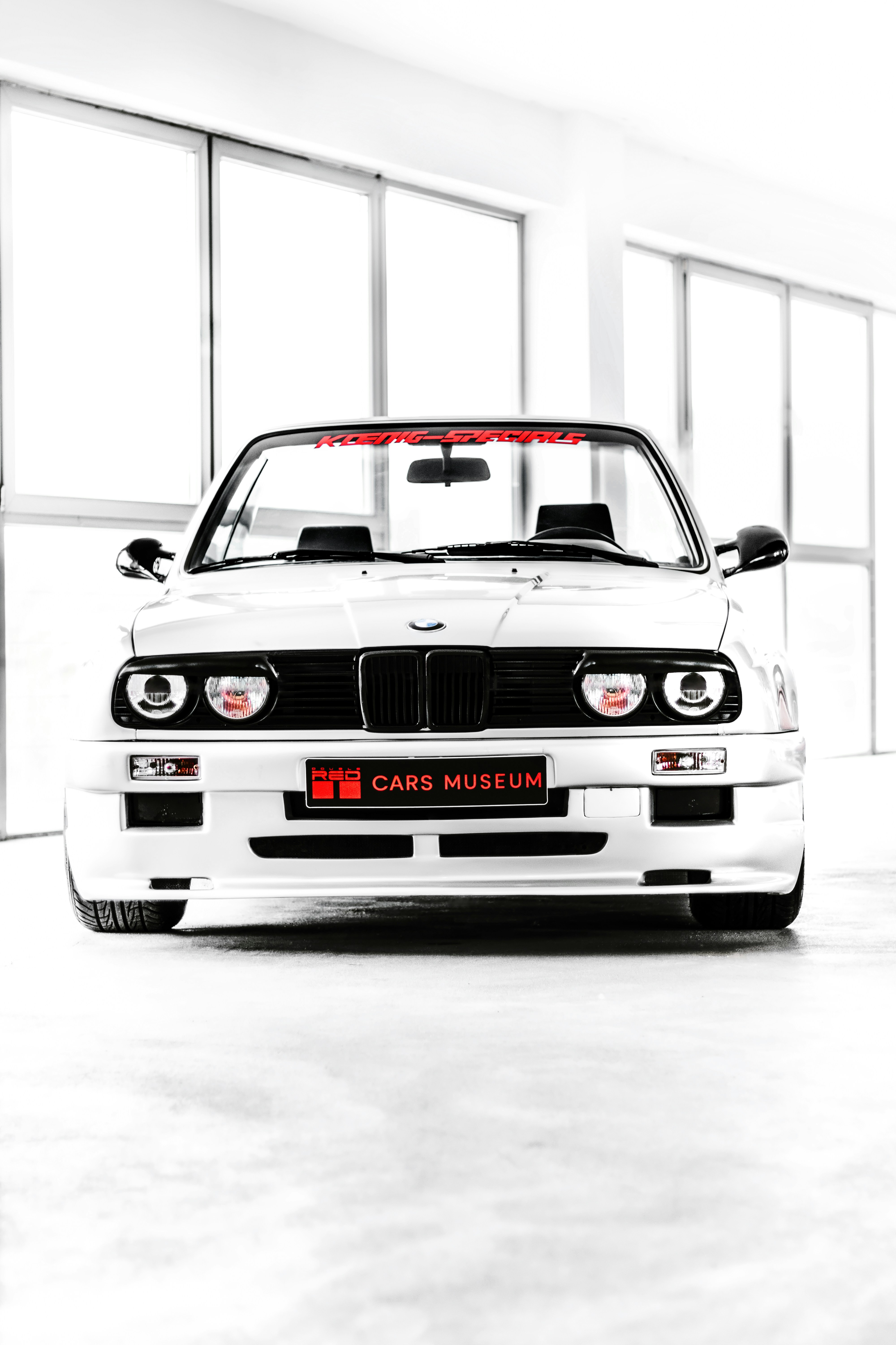 Front-Row BMW E36 in a Cars Museum showroom under bright studio light