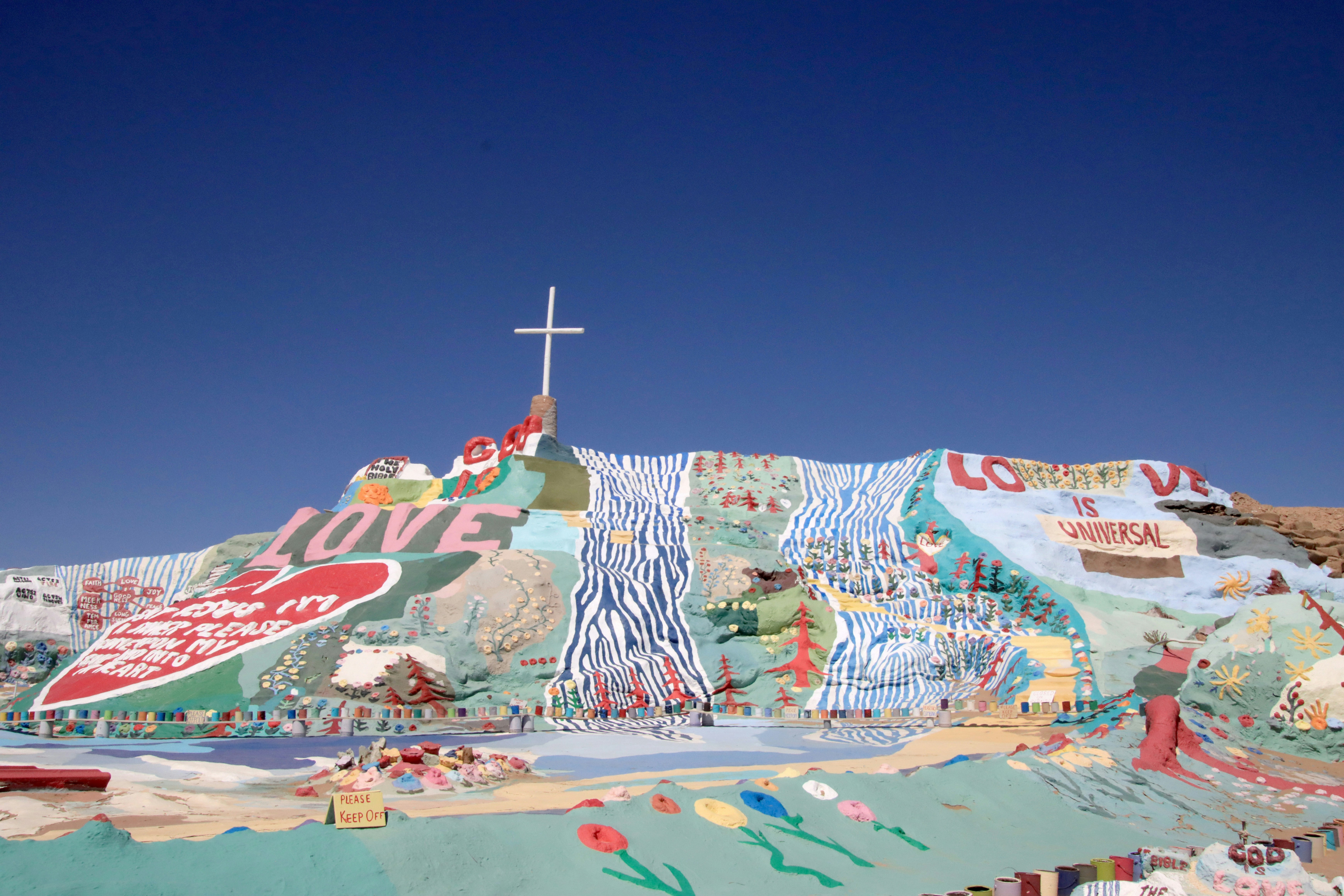 A cross on top of a hill covered in murals photo – Free Cross Image on ...
