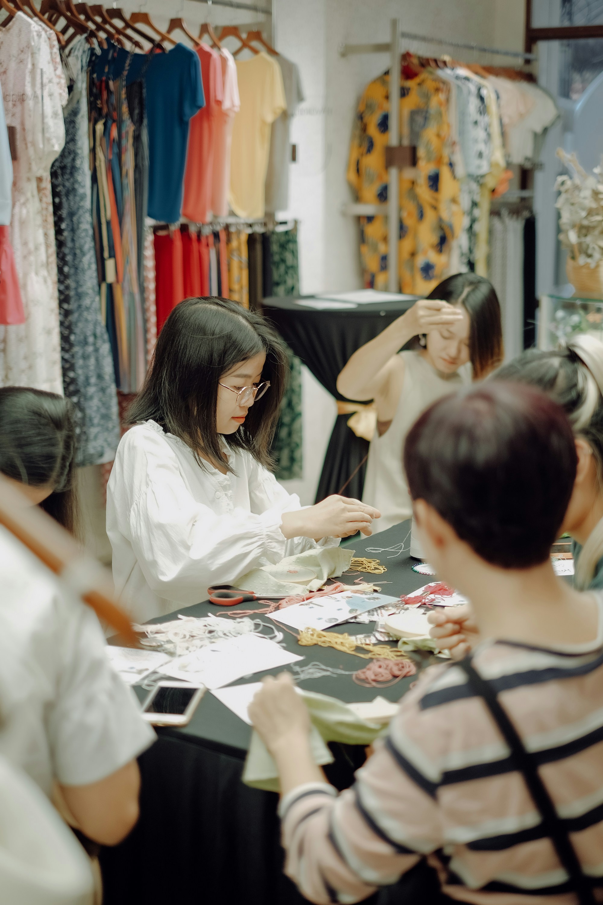 Fabric-Filled Studio: Hands Crafting Details Beneath a Rainbow of Garments