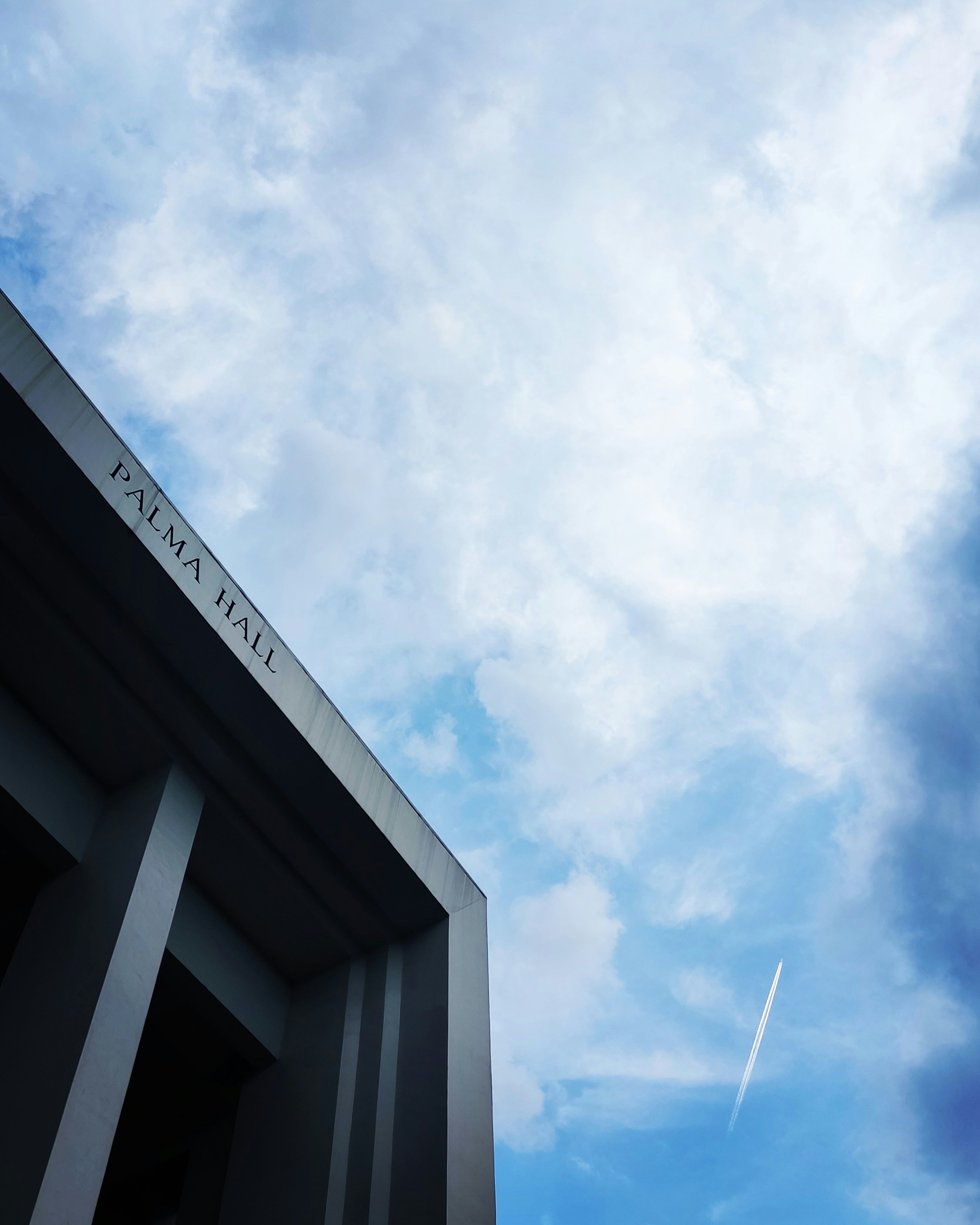 An airplane is flying in the sky above a building photo – Free Blue ...