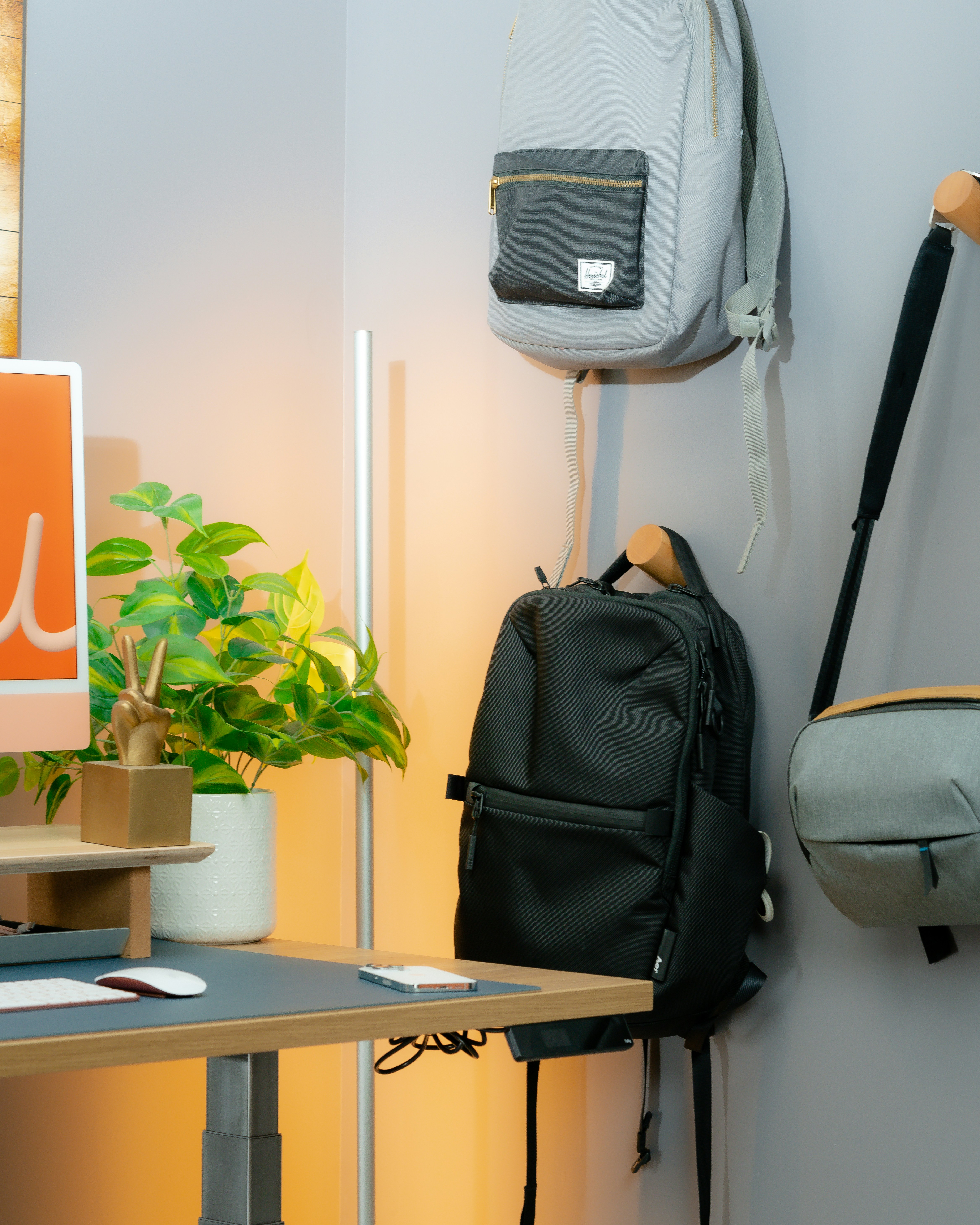 A backpack hanging on a wall next to a computer photo – Free Desk Image ...