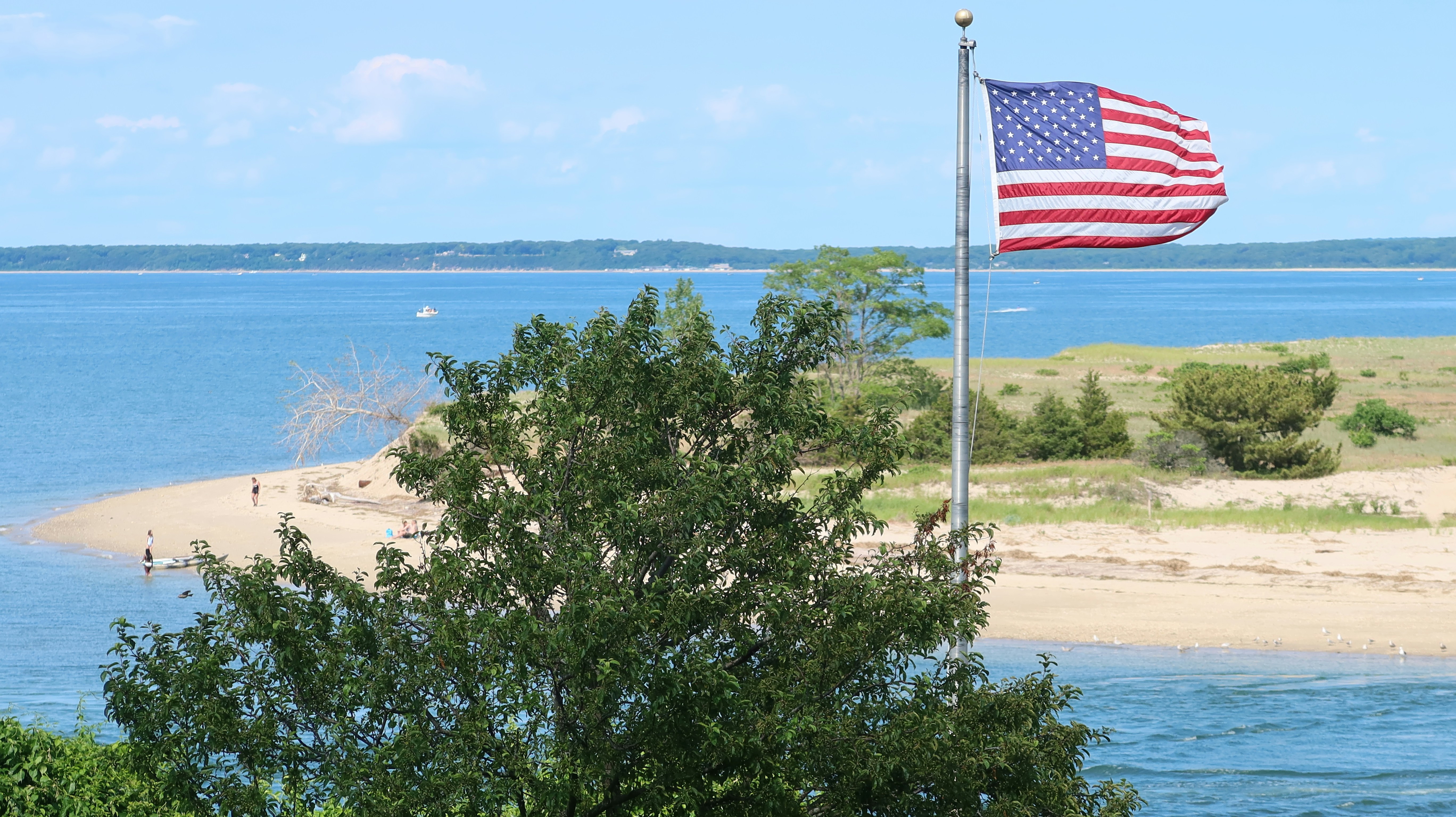 A large american flag flying over a beach next to a body of water photo ...