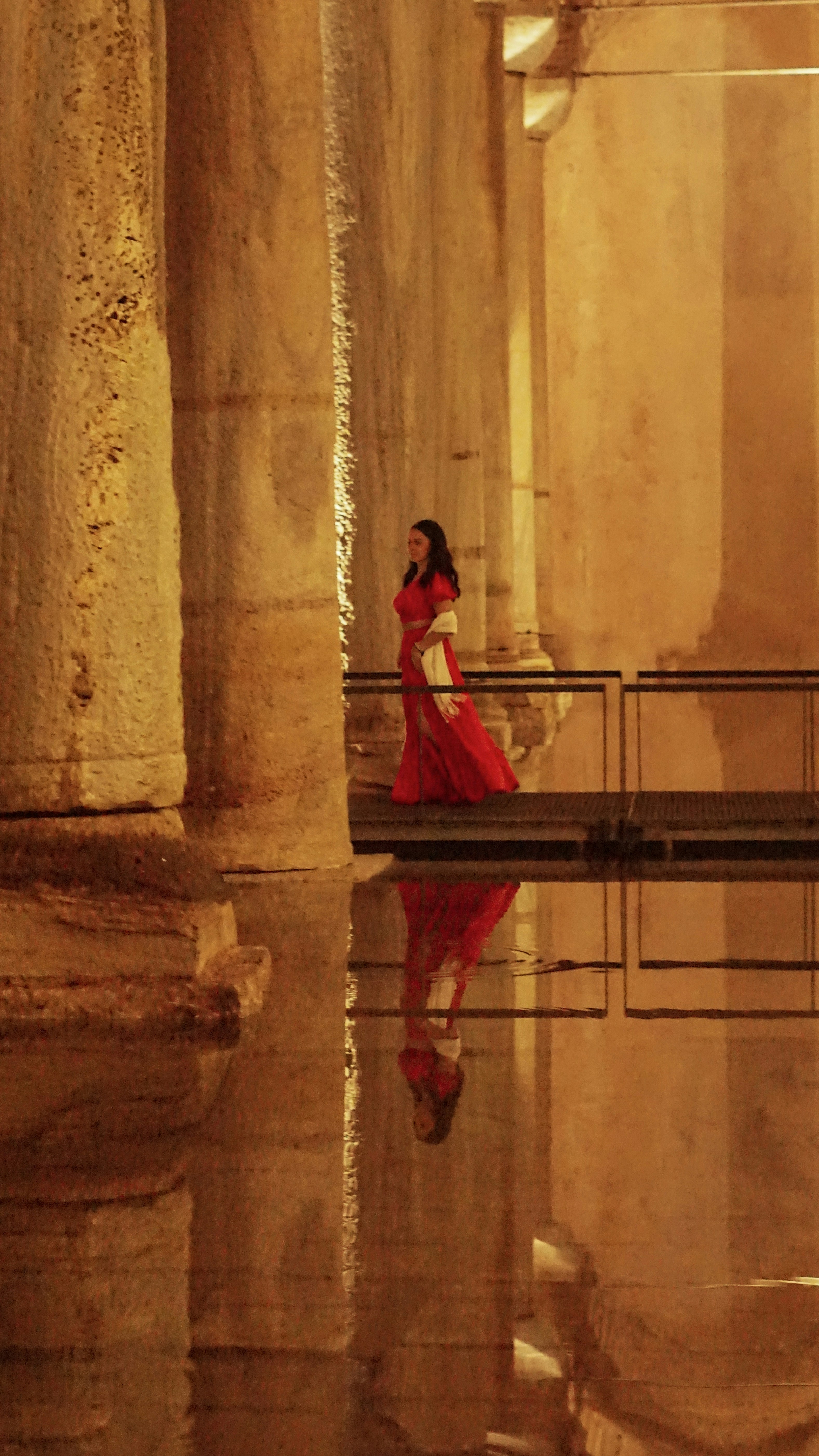 Red Silhouette Between Amber Pillars and Still Waters