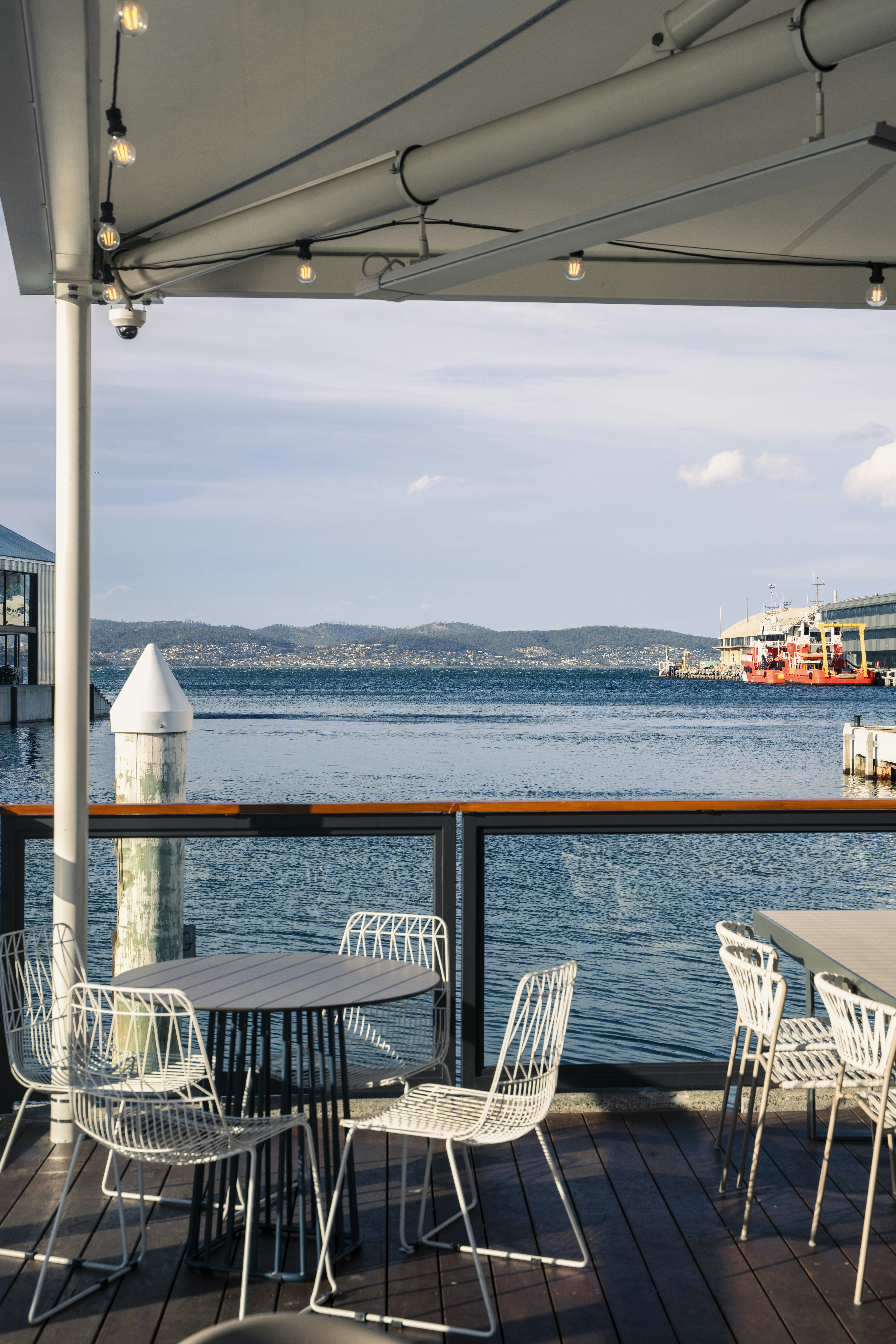 Pierside Geometry: White Wire Chairs Frame a Calm Harbor View