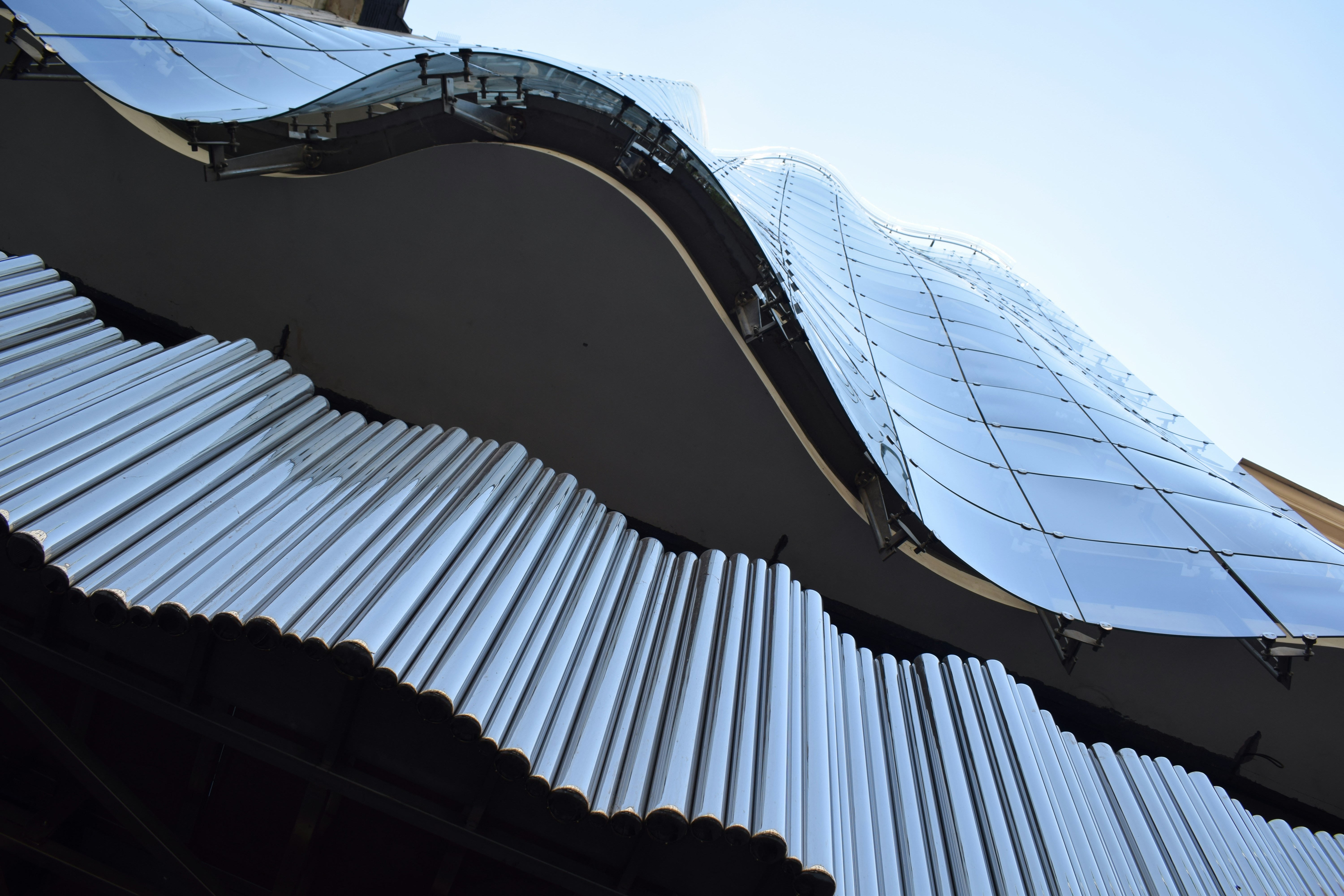 Curved Chrome Canopy: Flowing Lines Above a Corrugated Facade