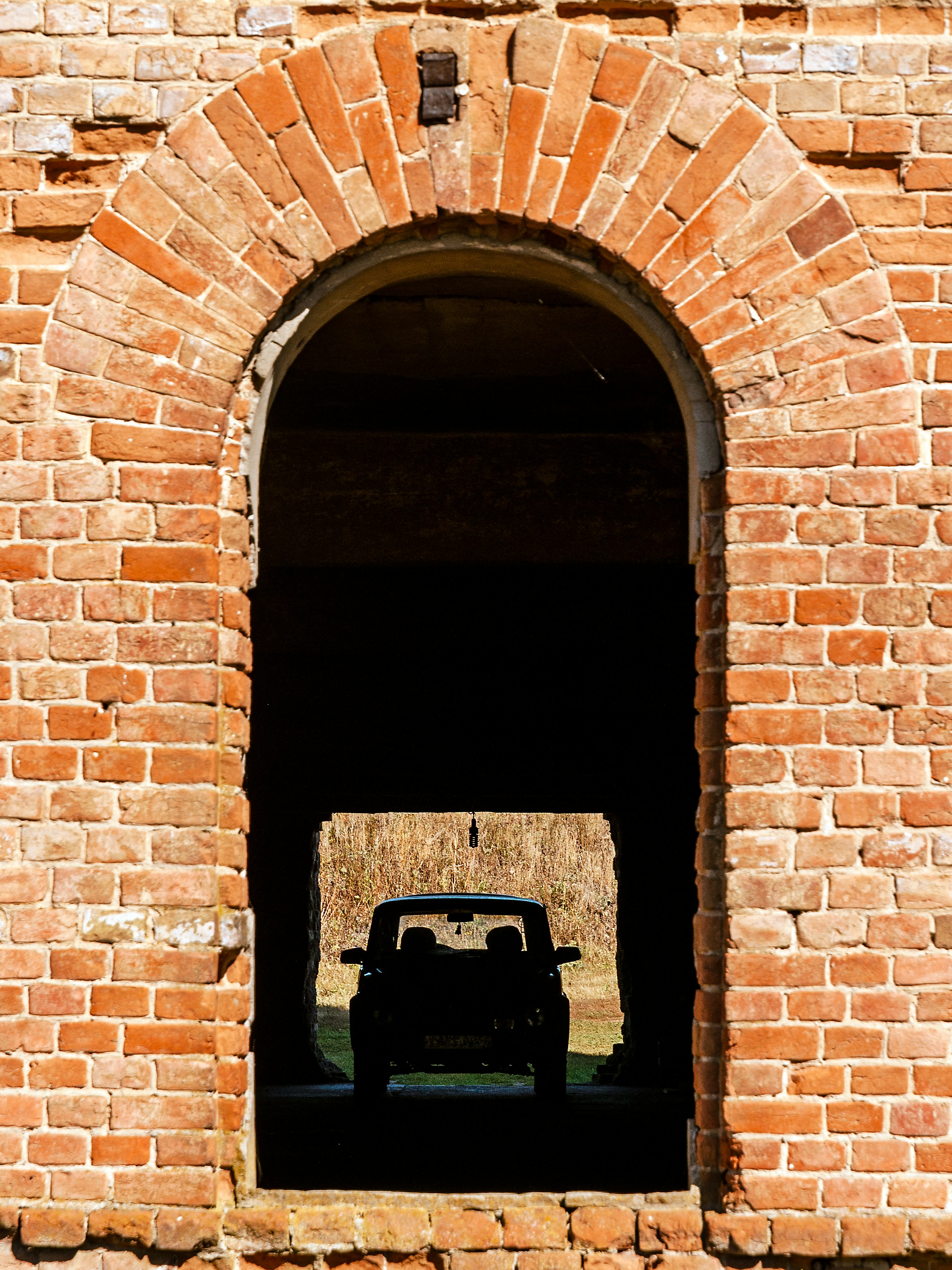 Between Brick Walls: A Jeep in the Shadowed Arch