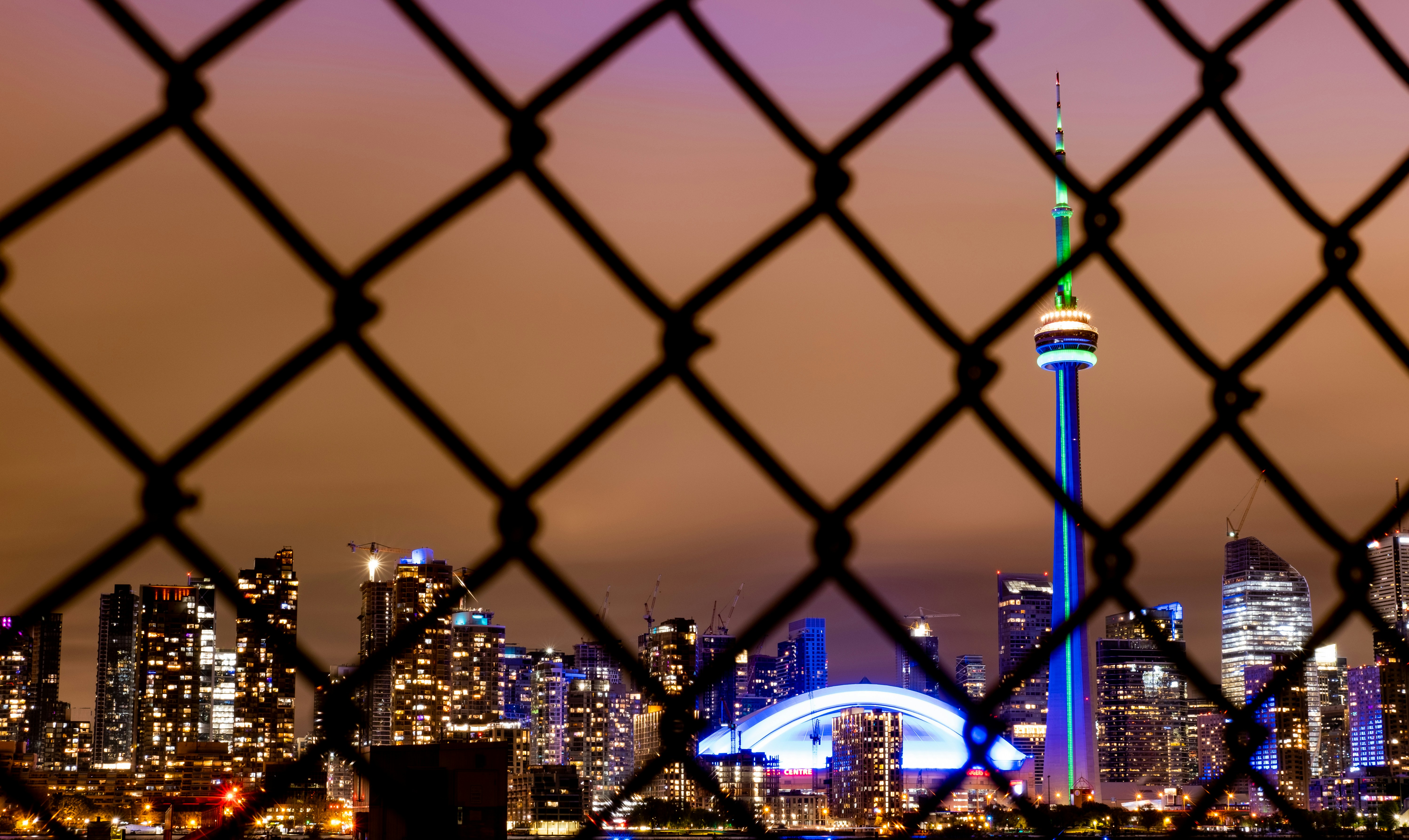 A city skyline seen through a chain link fence photo – Free Tower Image ...