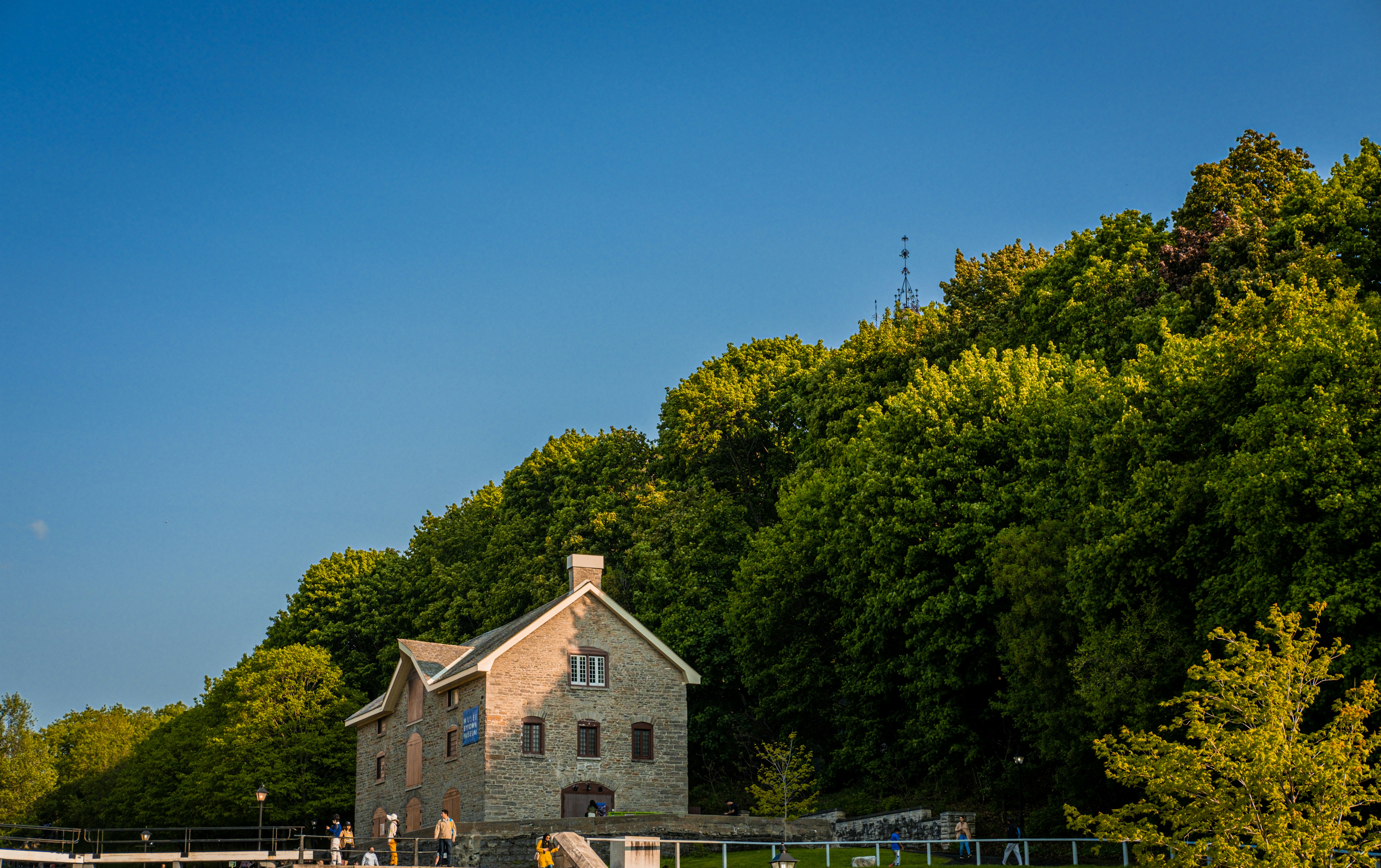 Stone Riverside Cottage Framed by a Lush Canopy Under a Clear Sky
