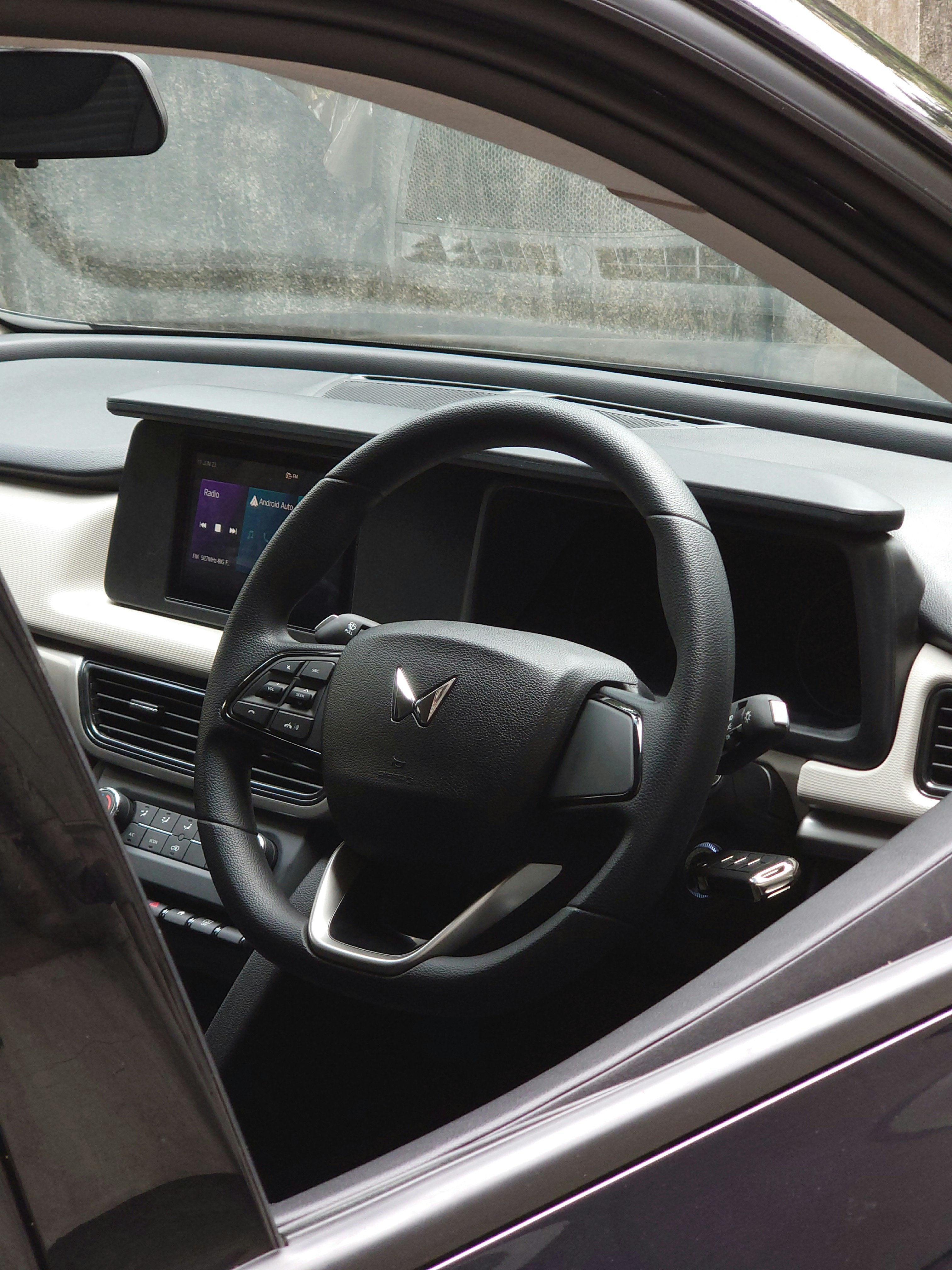 Interior of a modern car cockpit featuring a touchscreen display and a prominent steering wheel.