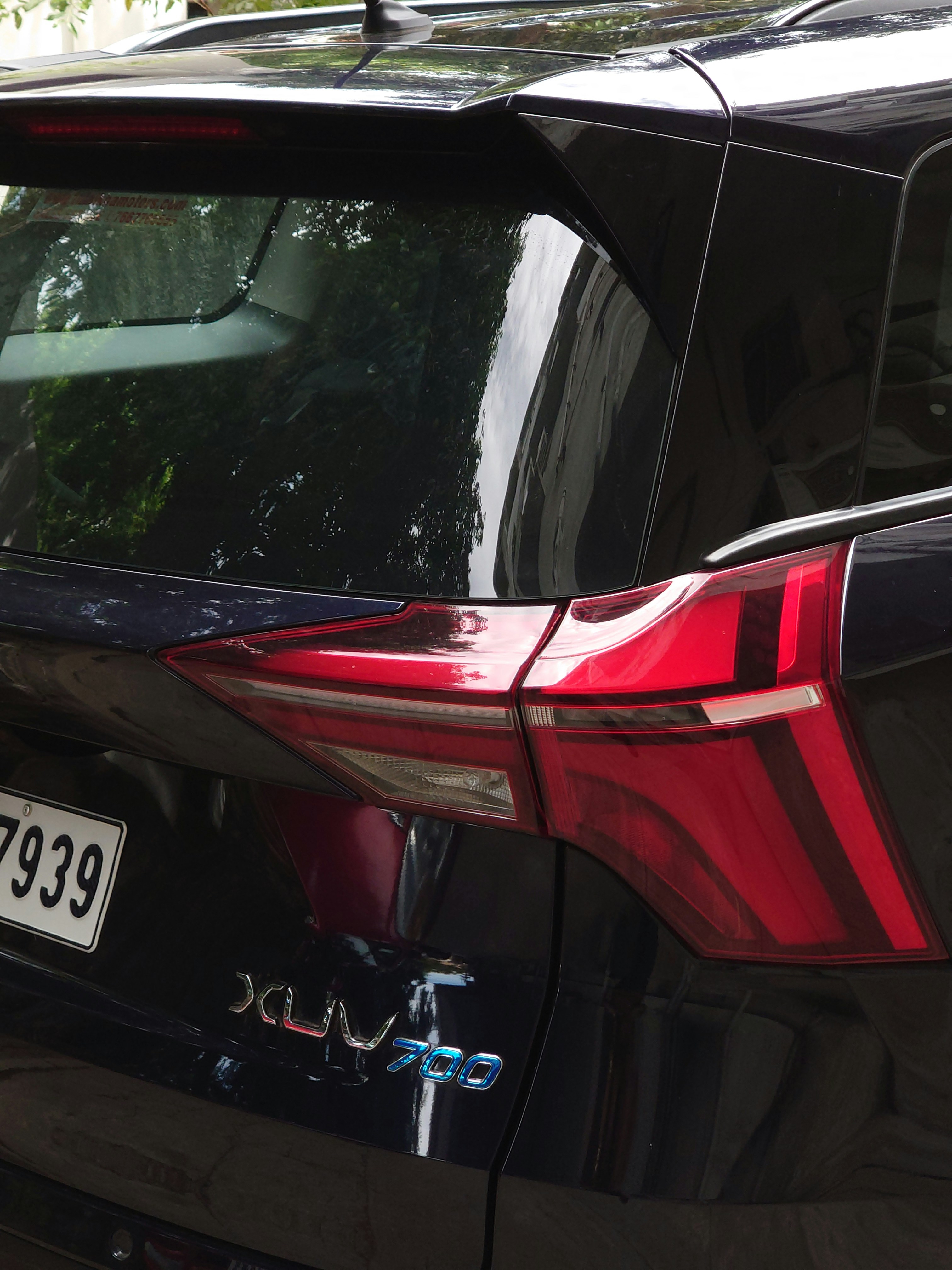 Photograph of a glossy black SUV rear, featuring the prominent red taillight and a partially visible license plate.