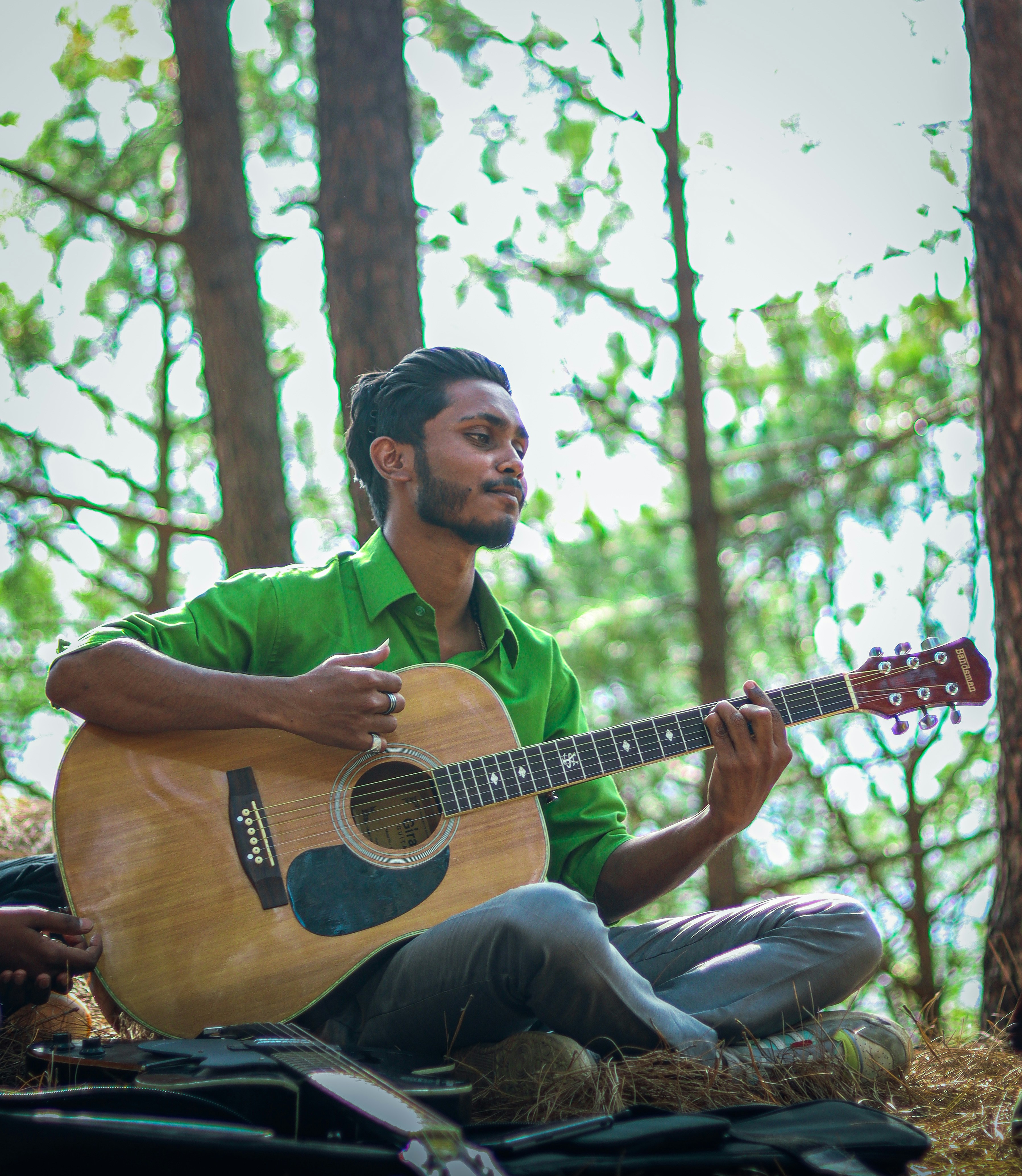 a man sitting in the woods playing a guitar
