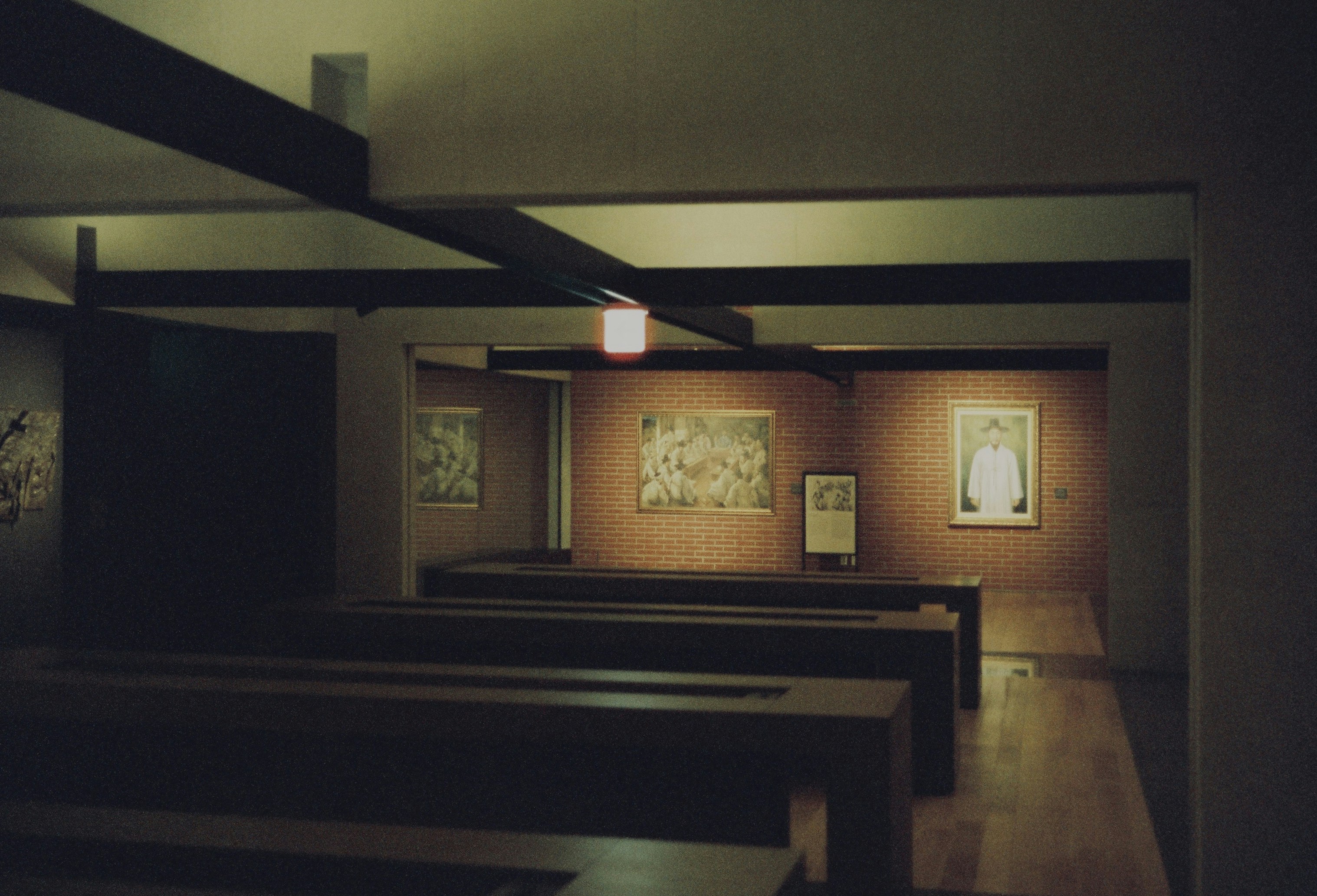 A dimly lit room with benches and pictures on the wall photo – Free Art ...