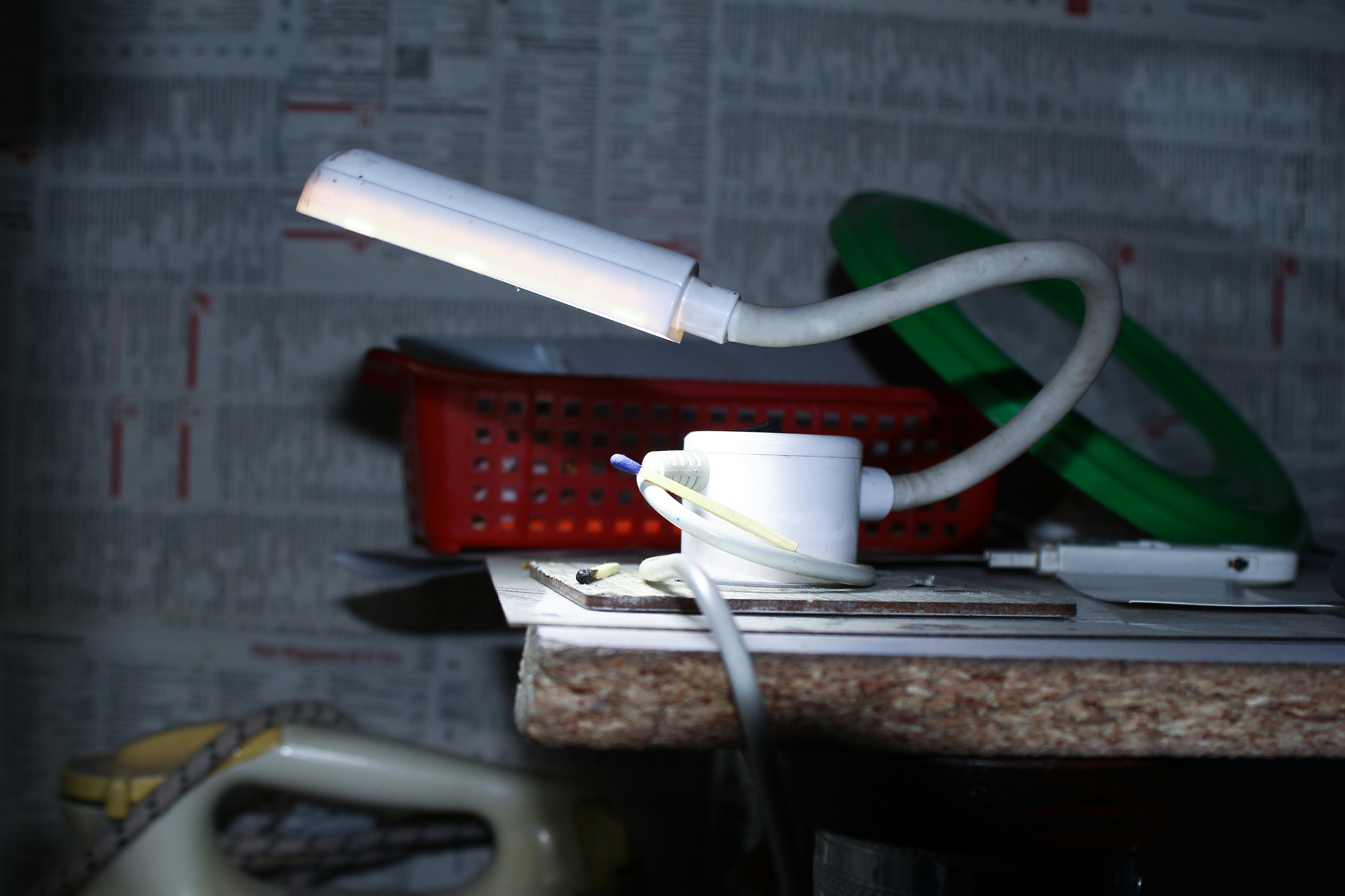 Wired Workshop: A cluttered power strip and tools under dim light