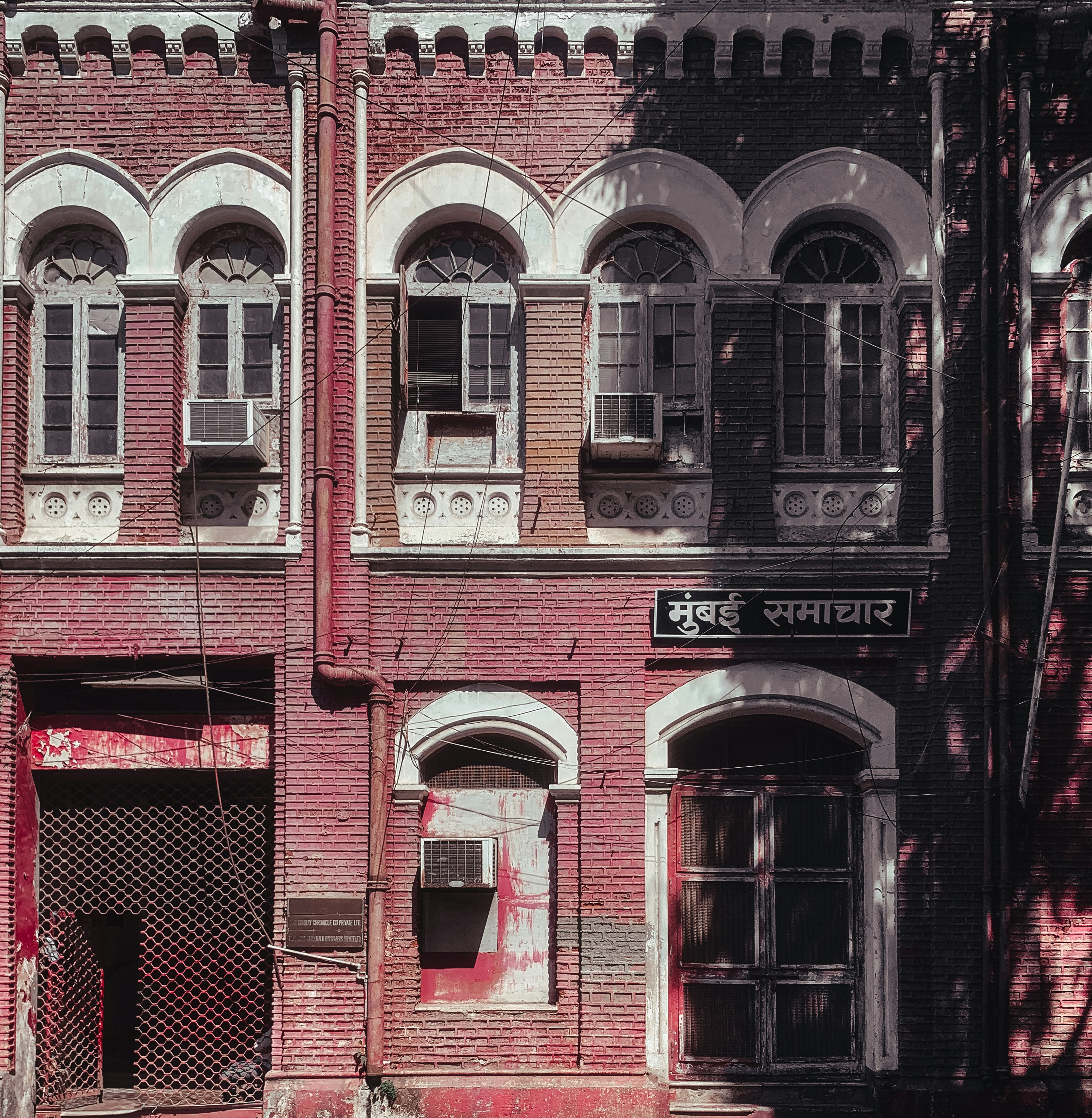 Un bâtiment en briques rouges avec des fenêtres cintrées et des volets ...