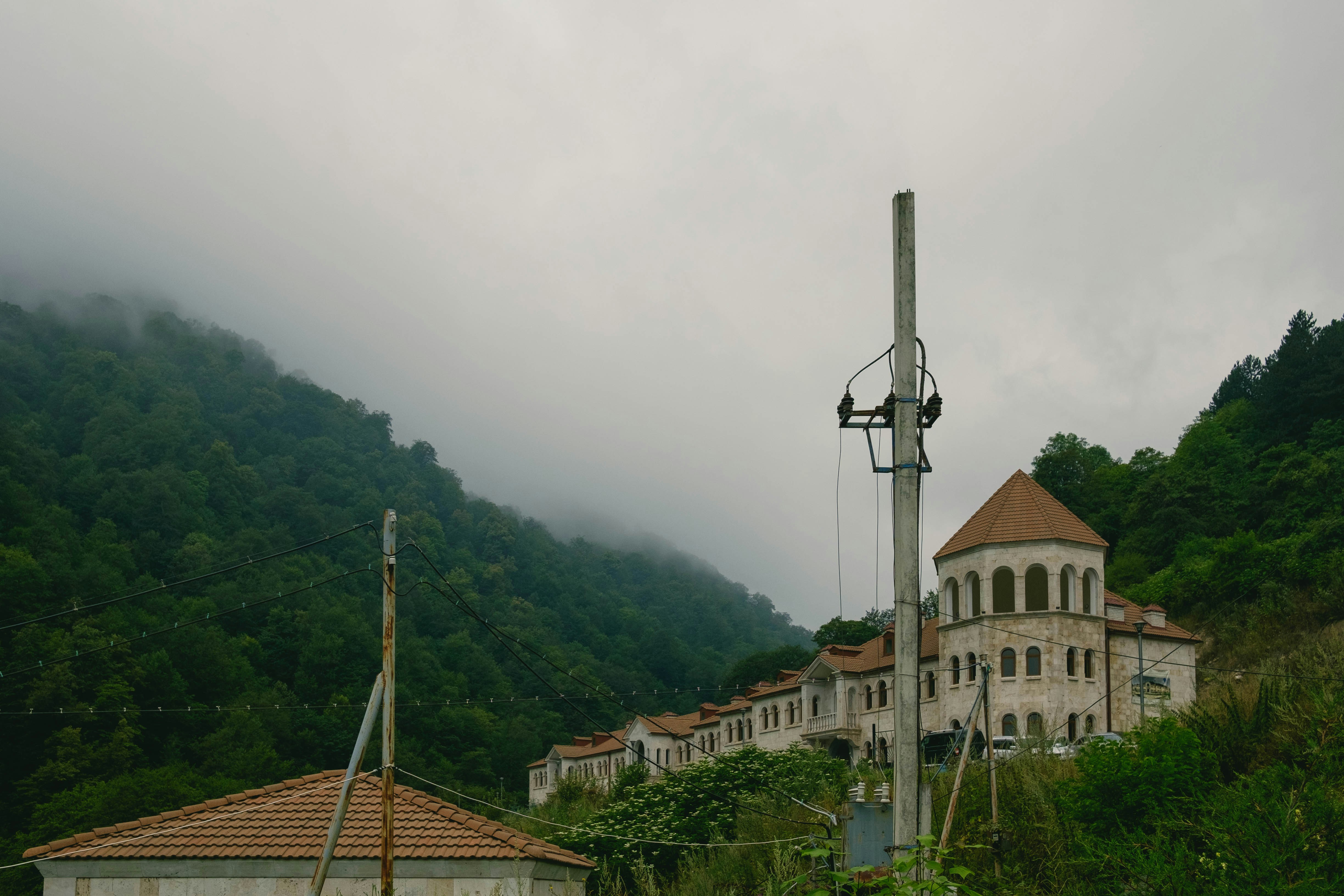 Fog-Wrapped Hillside Village: The Stone Church Among Green Ridges