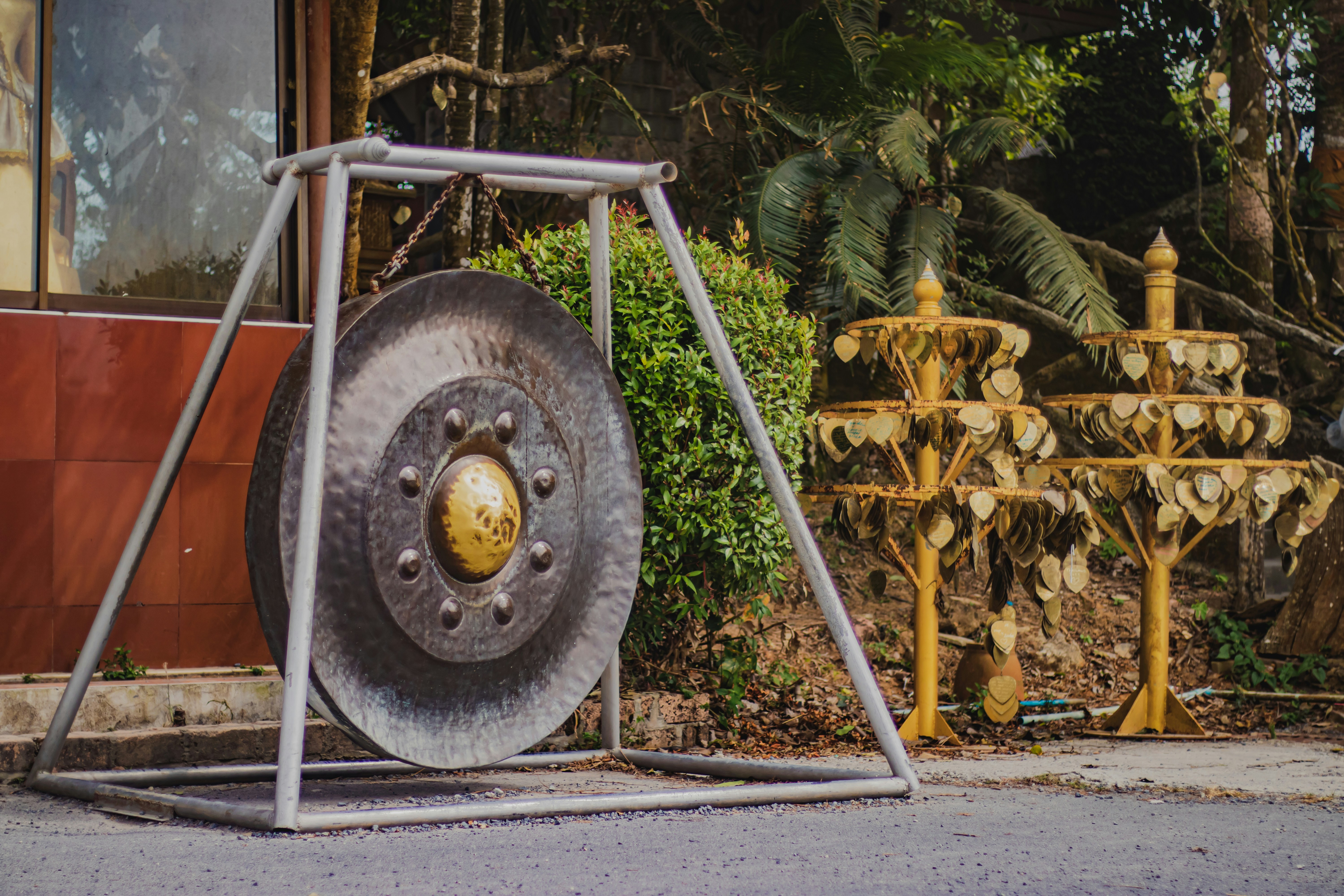 Gong on a Metal Frame Beside a Tiered Brass Fountain in a Quiet Garden