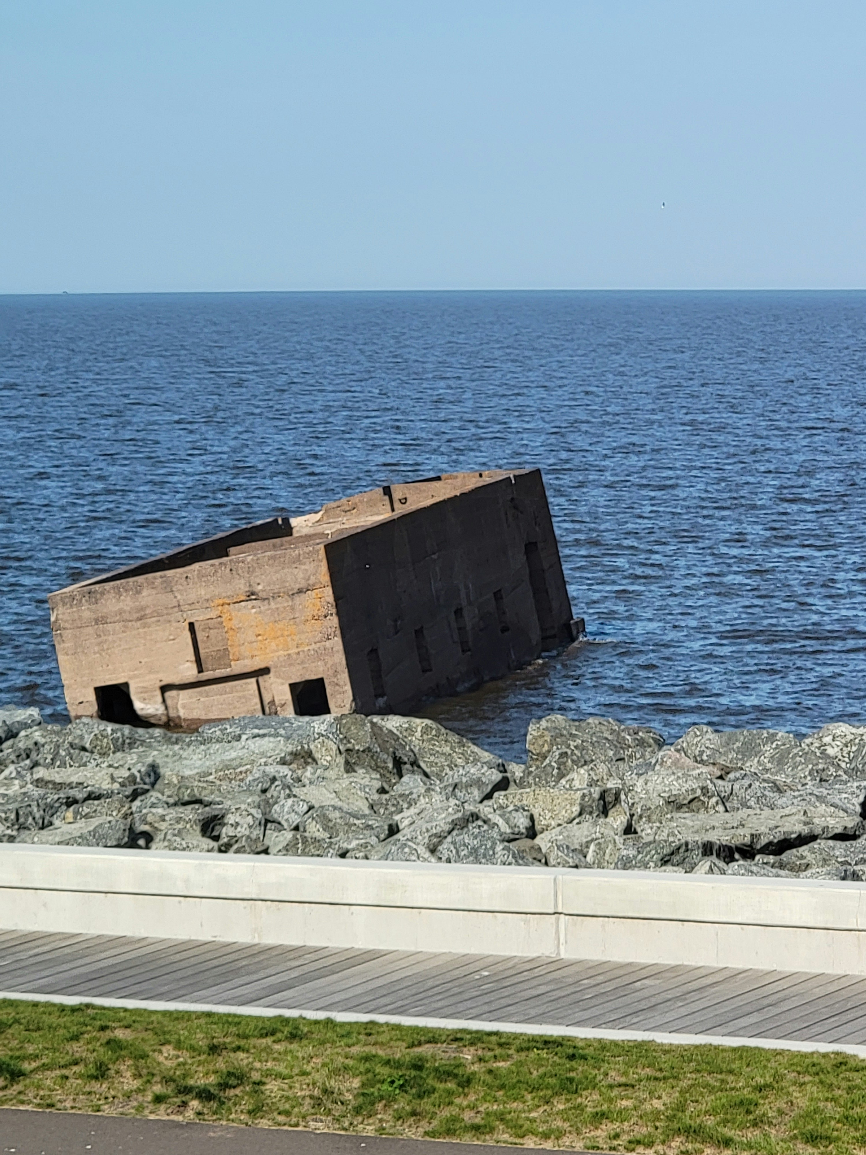 Ruined Concrete Bunker in Calm Sea—A Quiet Harbor Breakwater Scene