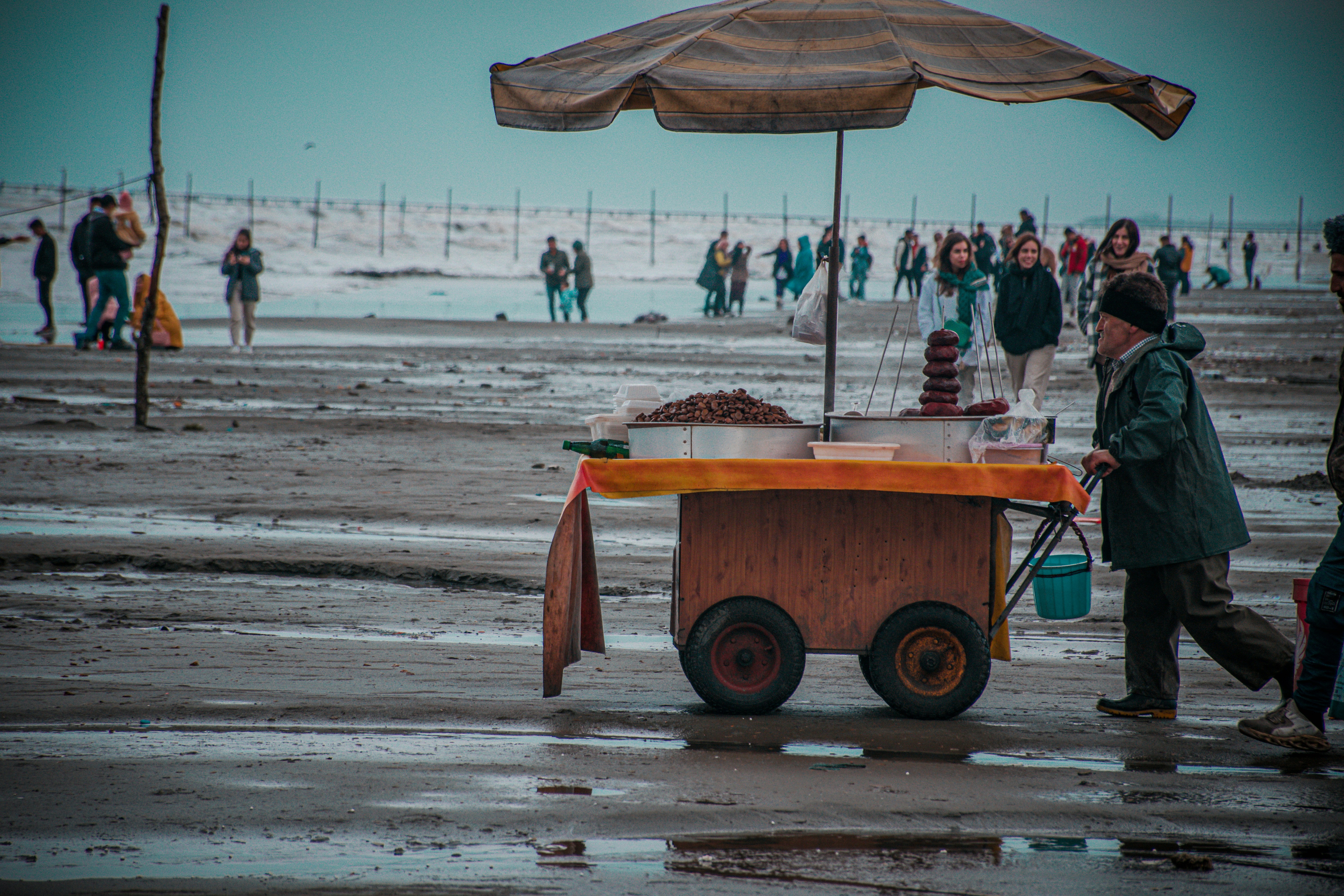 Amber Cart Under a Weathered Umbrella on a Muddy Seaside