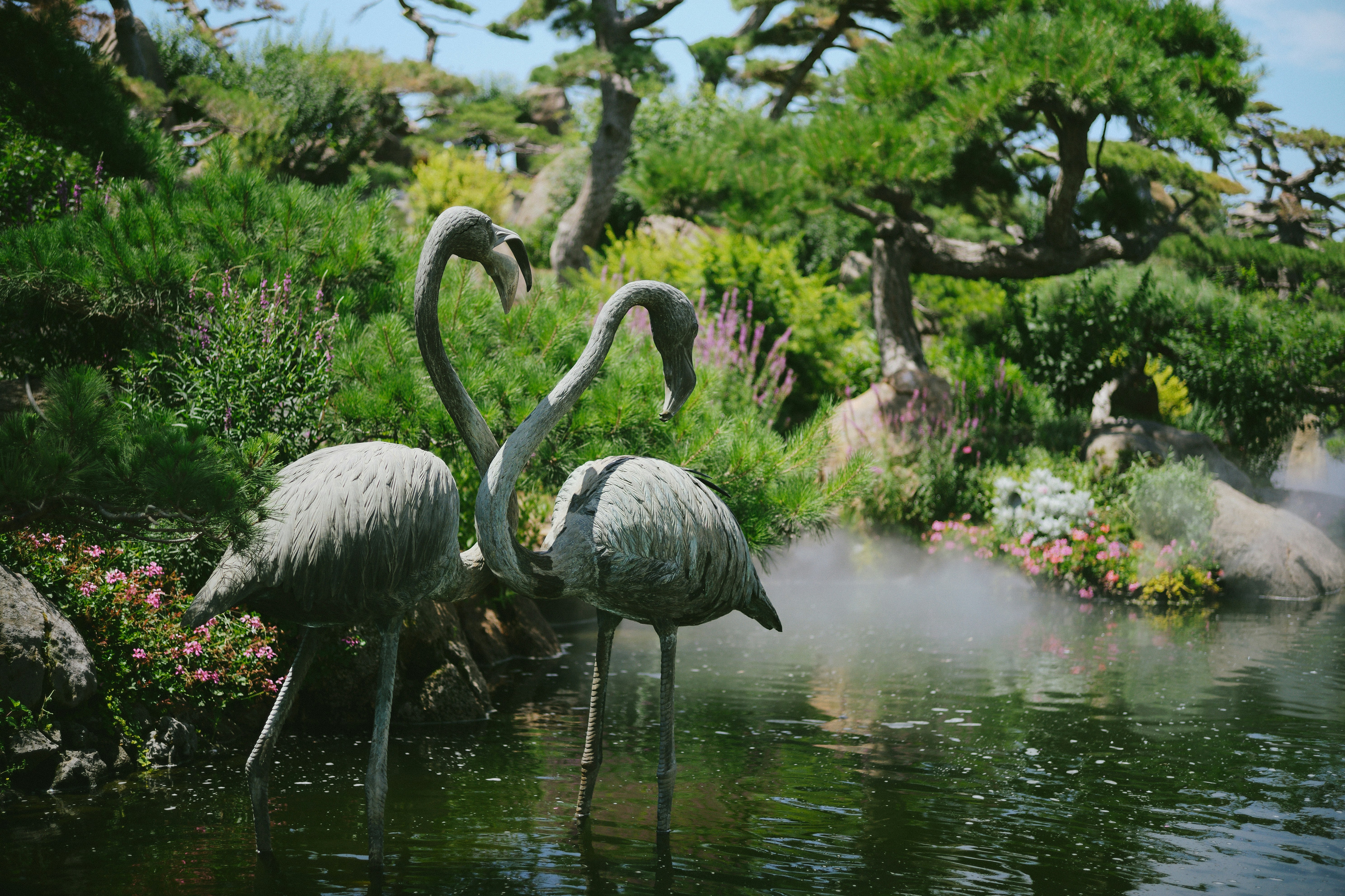Bronze Flamingos in a Mist-Kissed Garden Pond