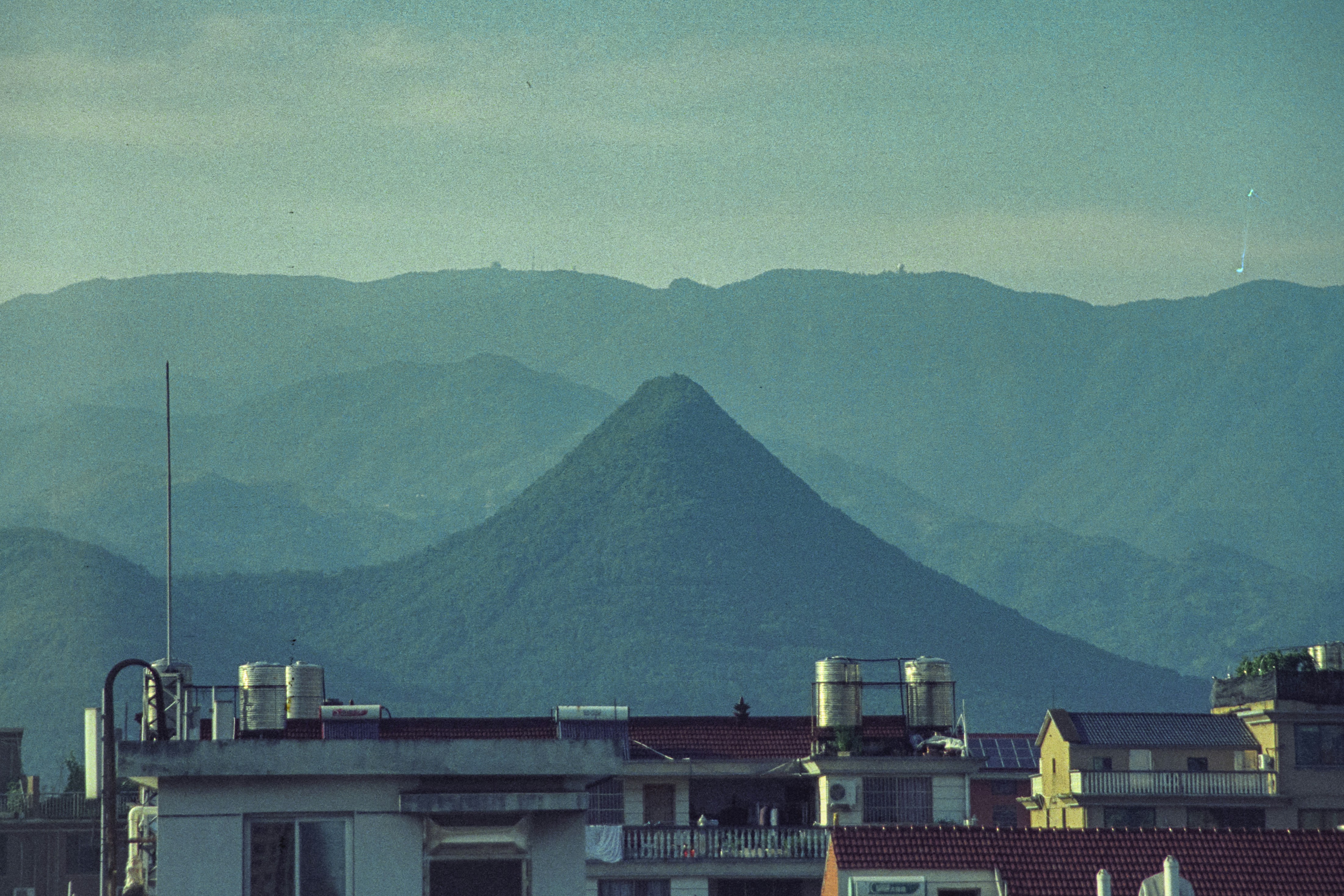 Urban skyline foreground with the distinct silhouette of Jianfeng Mountain under a clear sky.