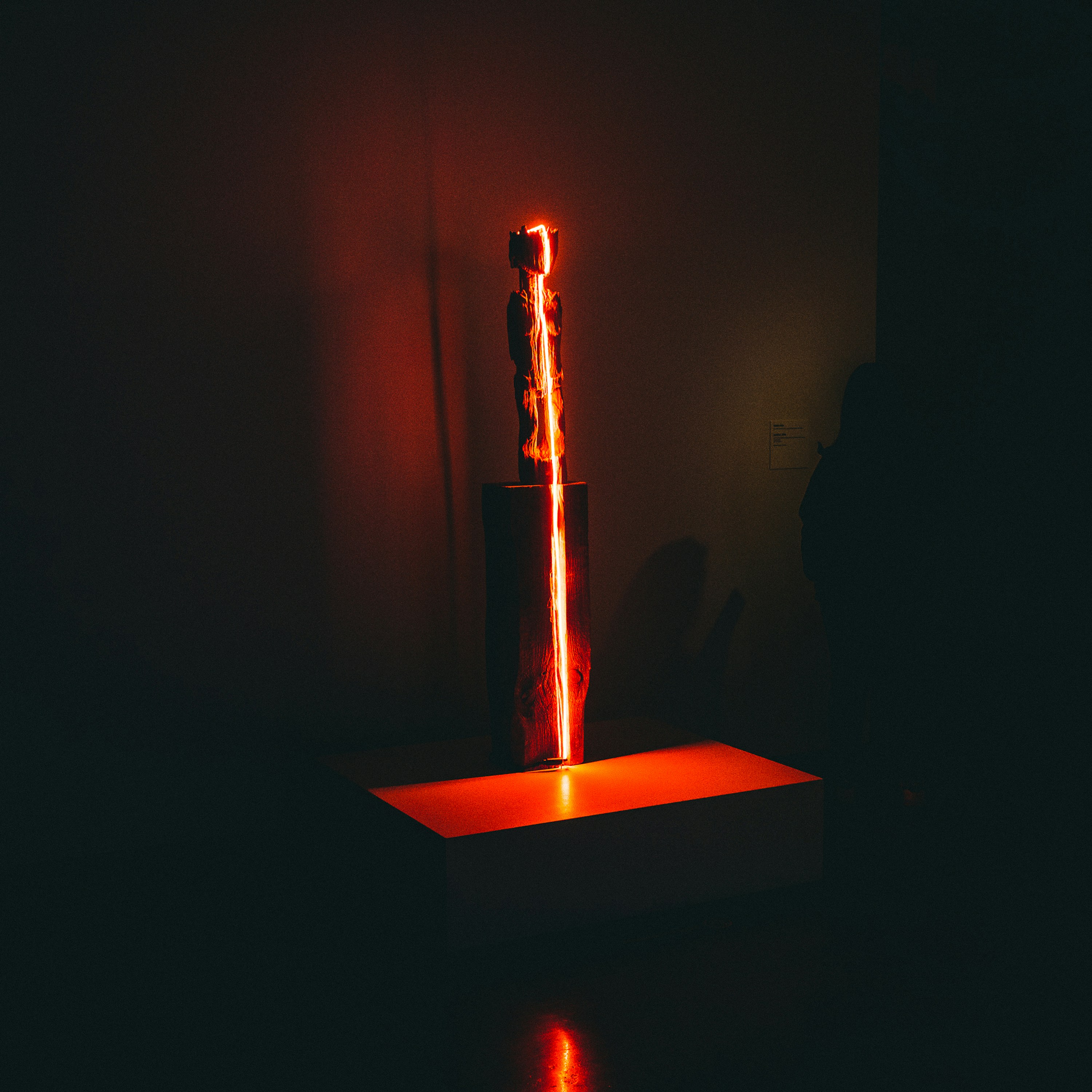 Vertical Ember: A solitary crimson column awakening a dark gallery