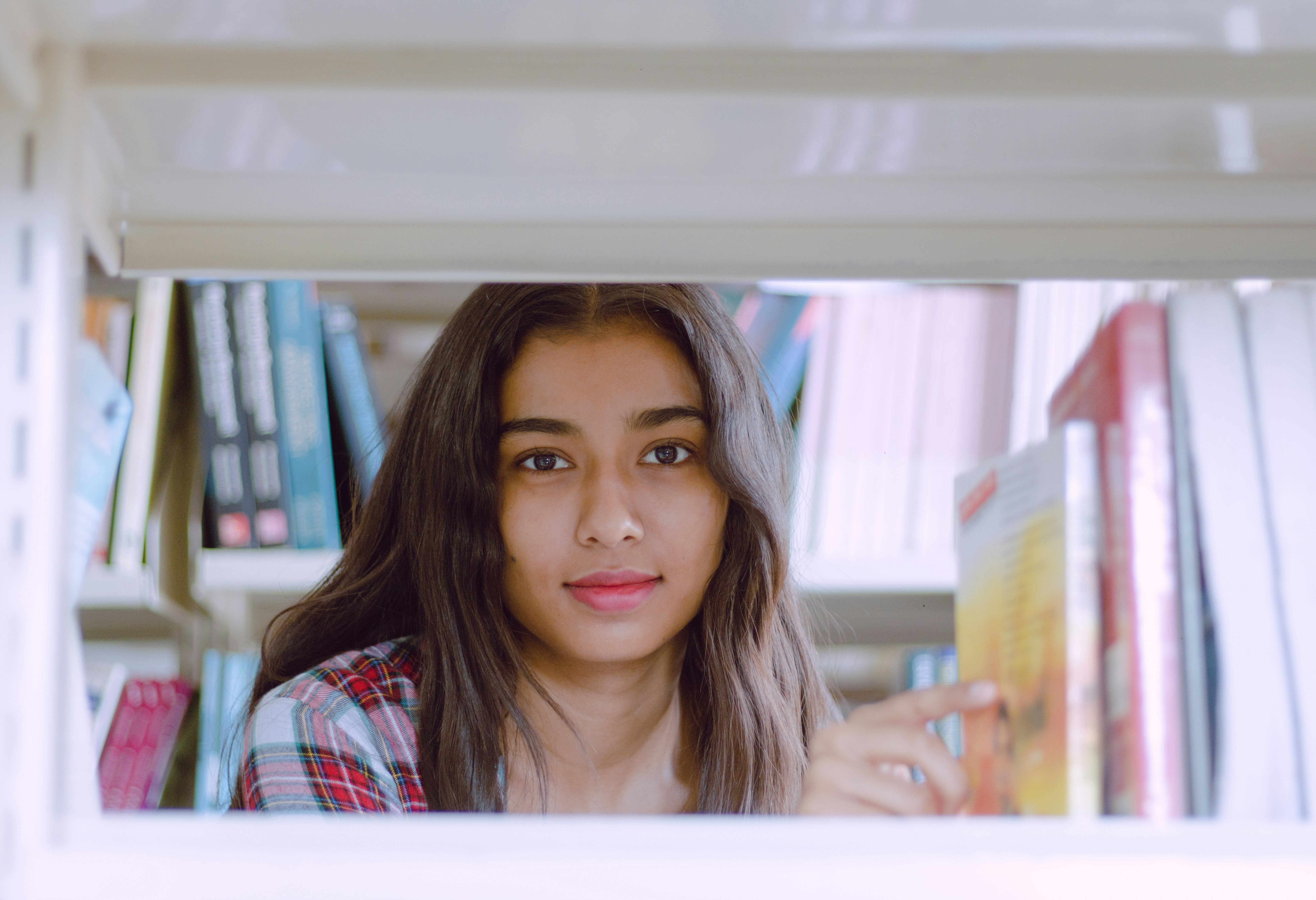 A girl looking through a window at a book shelf photo – Free Girl Image ...