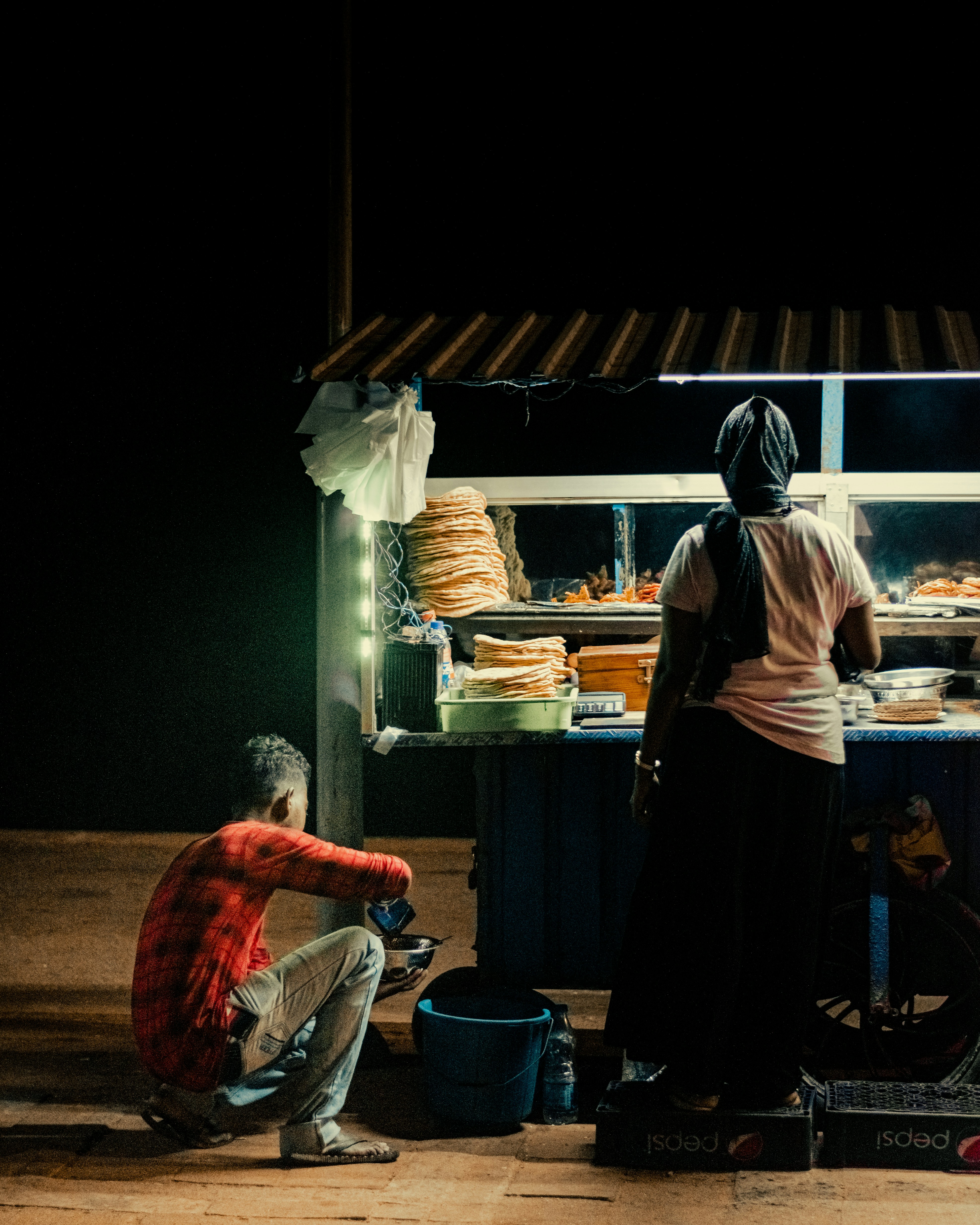 Under Night Lights: Stacked Flatbreads and a Quiet Customer at a Street Stall