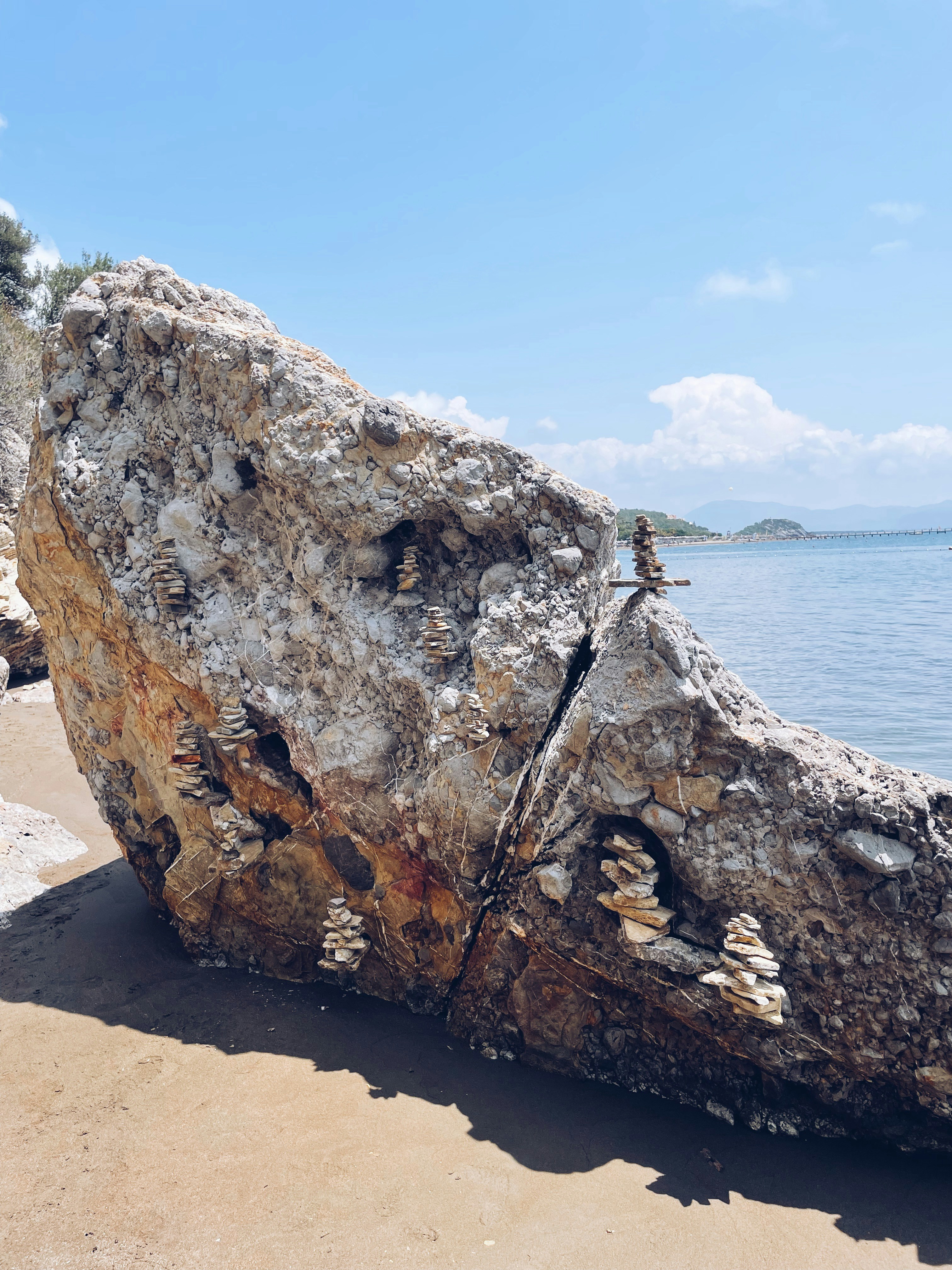 Cairns on a Weathered Rock: A Sunlit Beach Composition