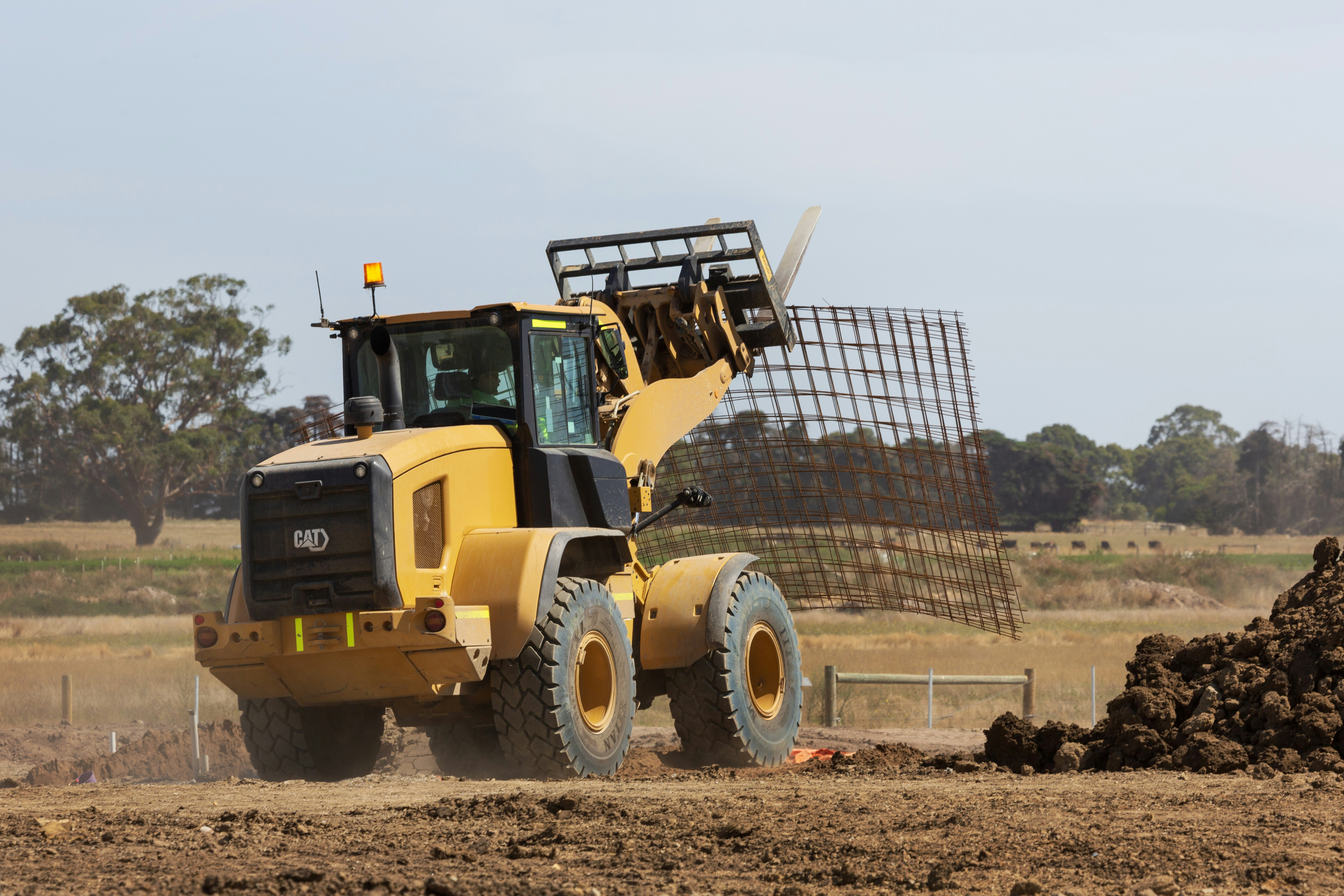 A large yellow construction vehicle driving down a dirt road photo ...