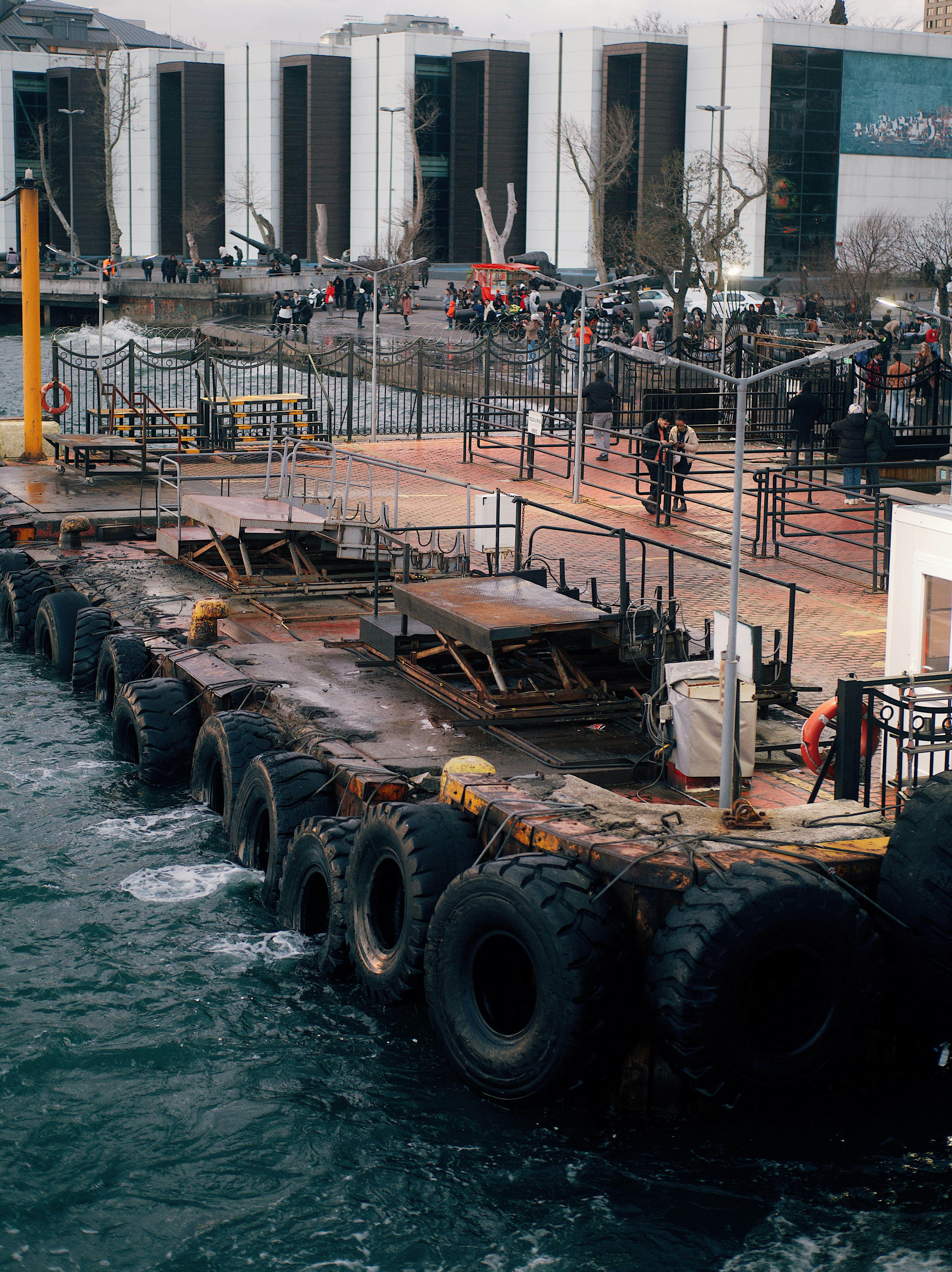 Edge of the Tide: A Busy Waterfront Pier Framed by Industrial Tires