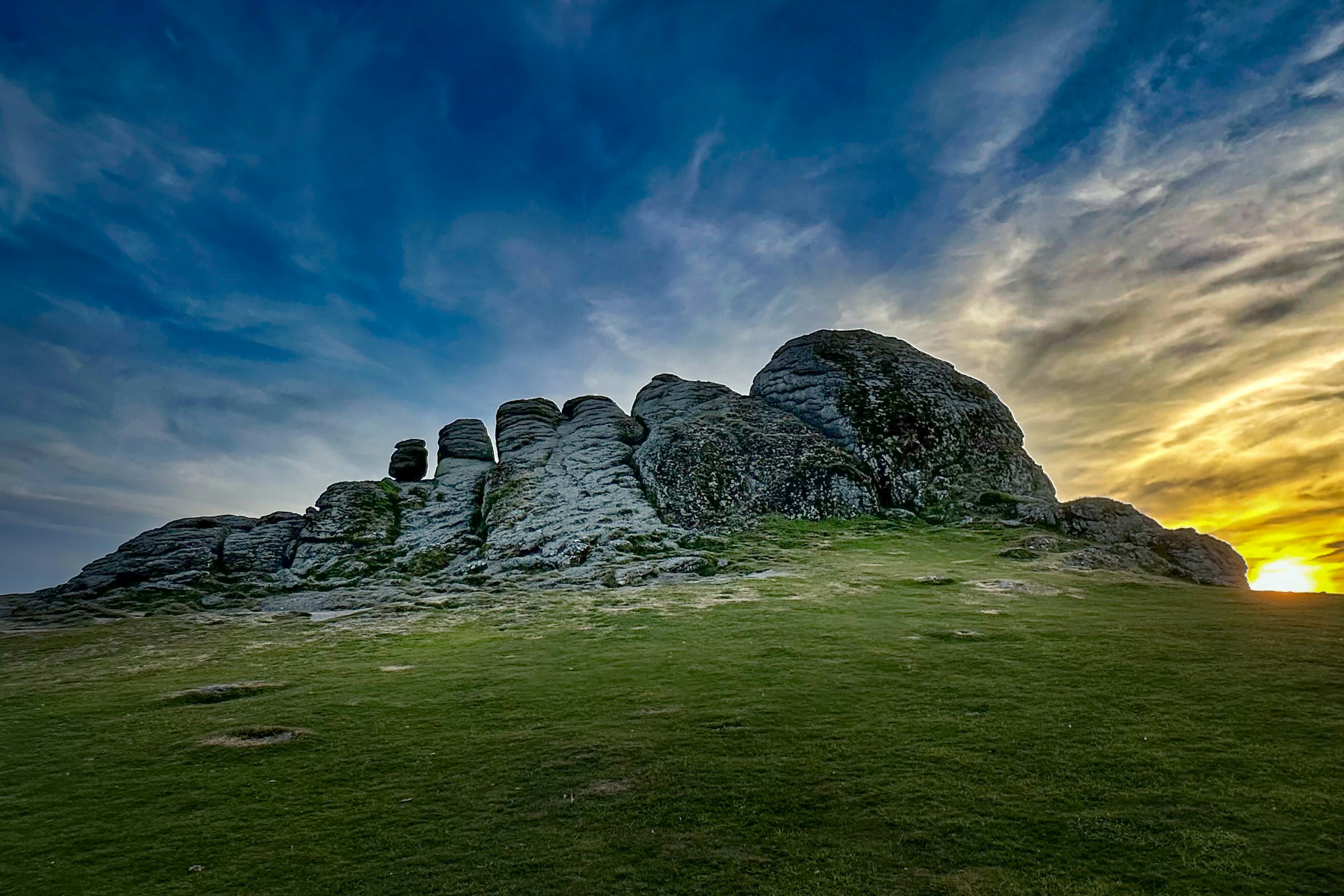 A large rock formation sitting on top of a lush green field photo ...