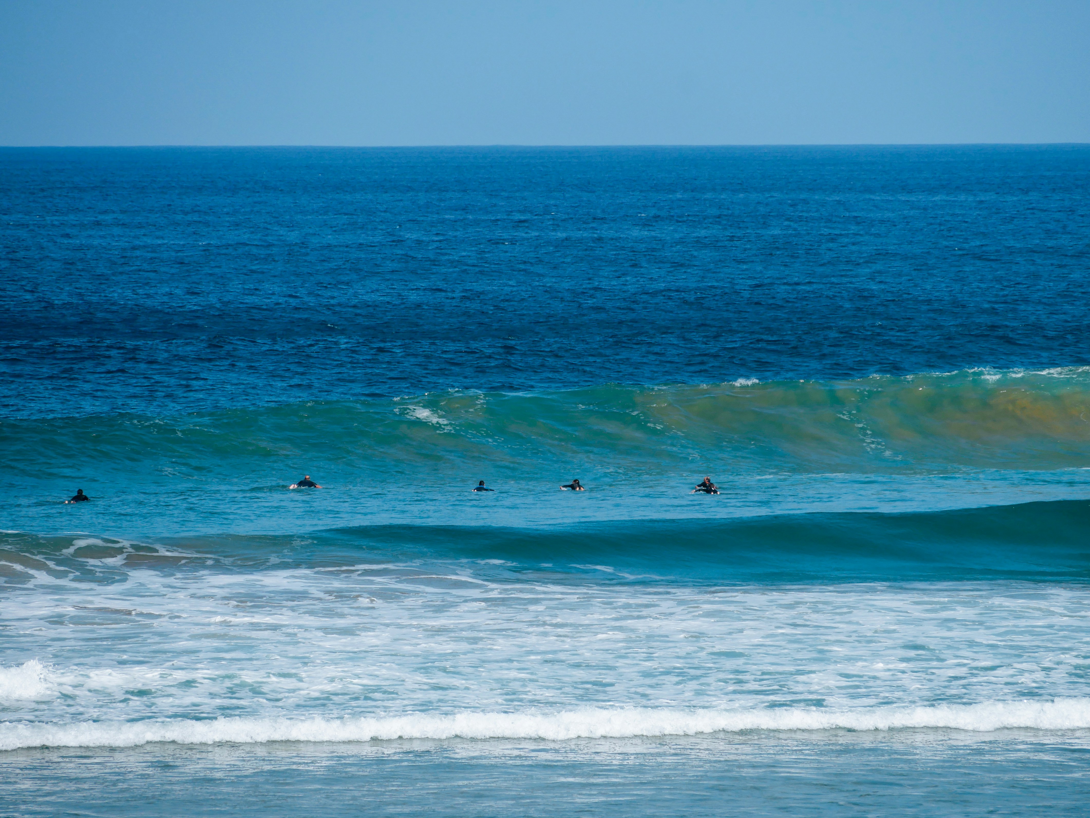 A group of people riding waves on top of surfboards photo – Free Spain ...