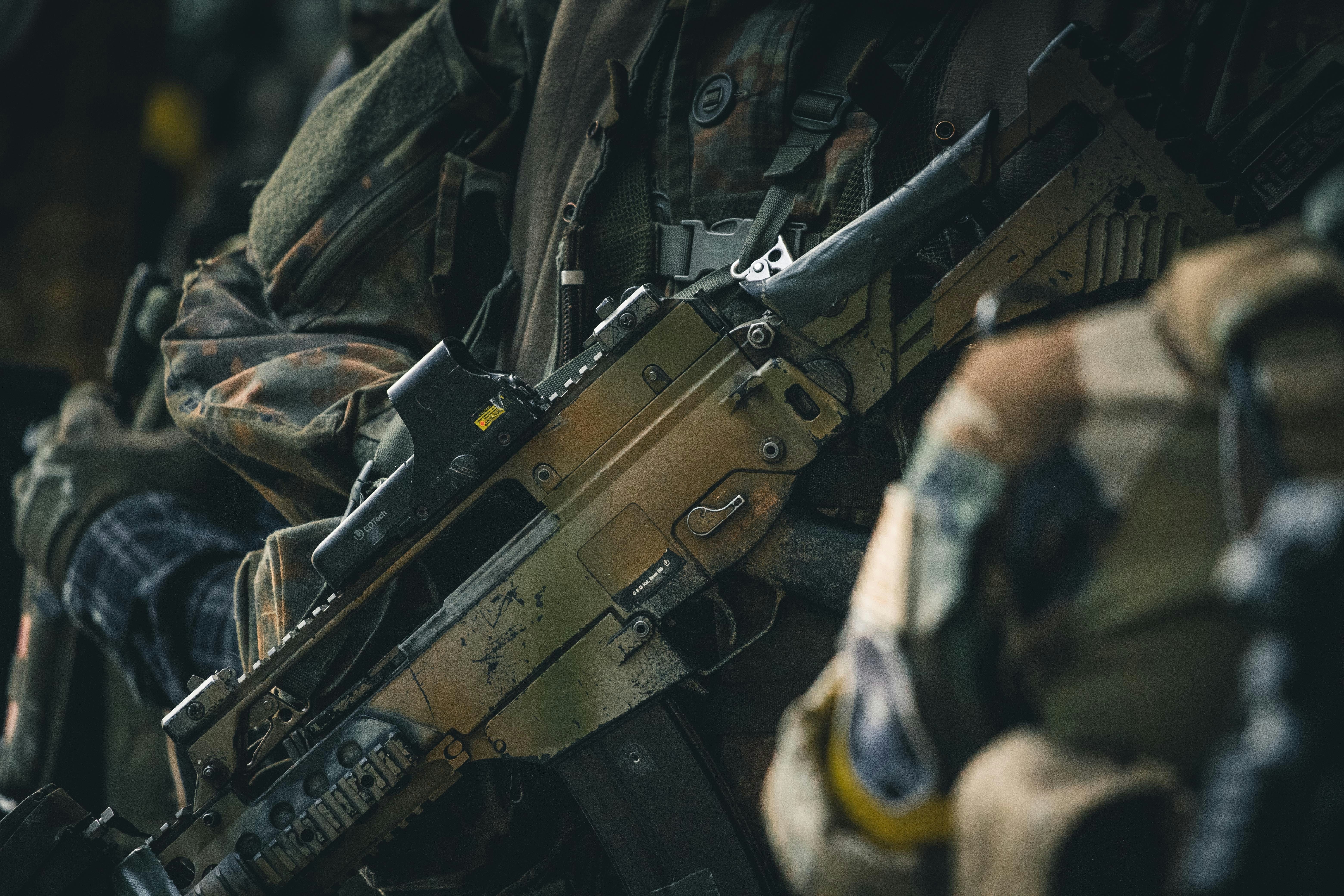 A close up of a rifle on a person's arm photo – Free Gun Image on Unsplash