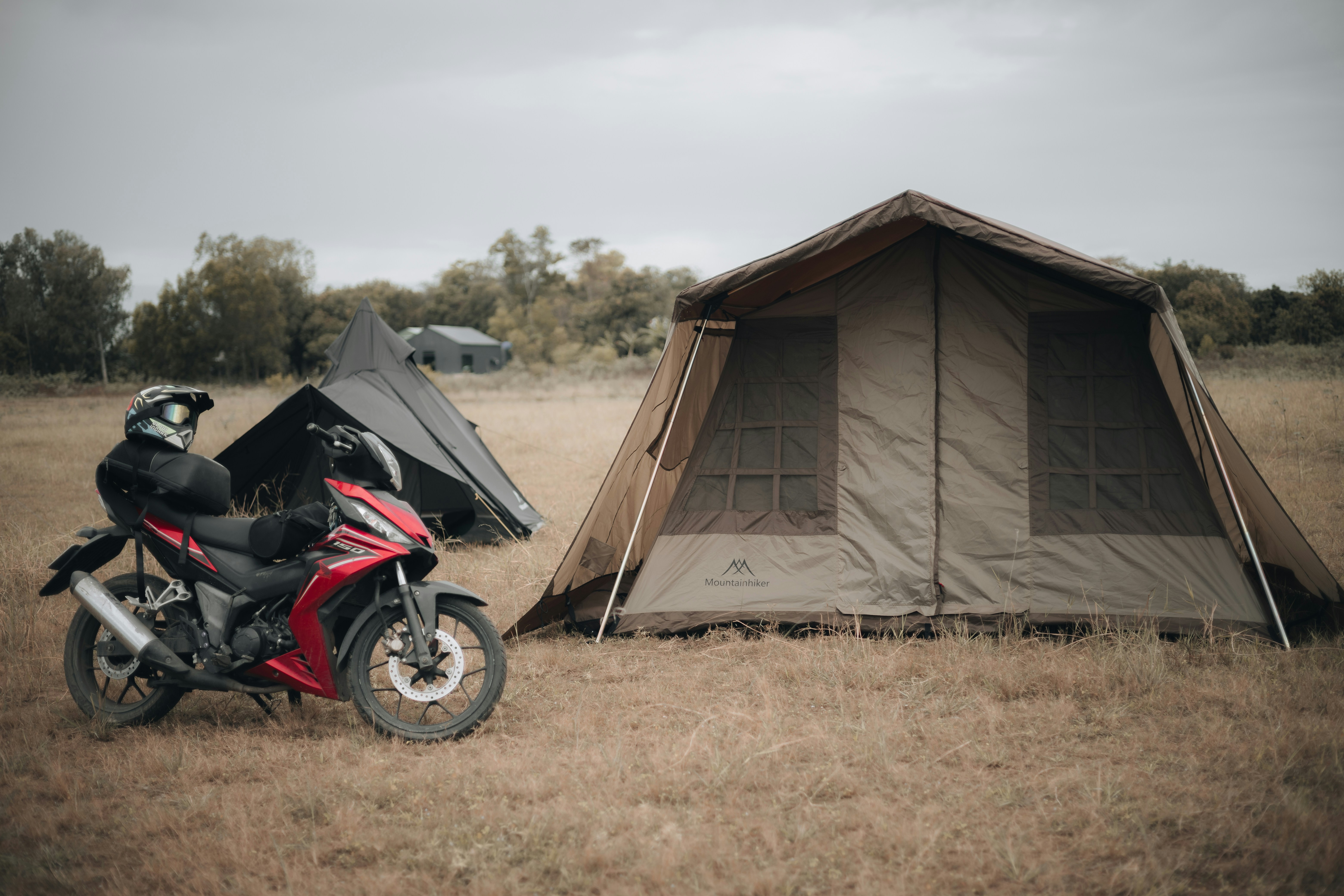 Red Motorcycle at a Quiet Campsite with Canvas Tents