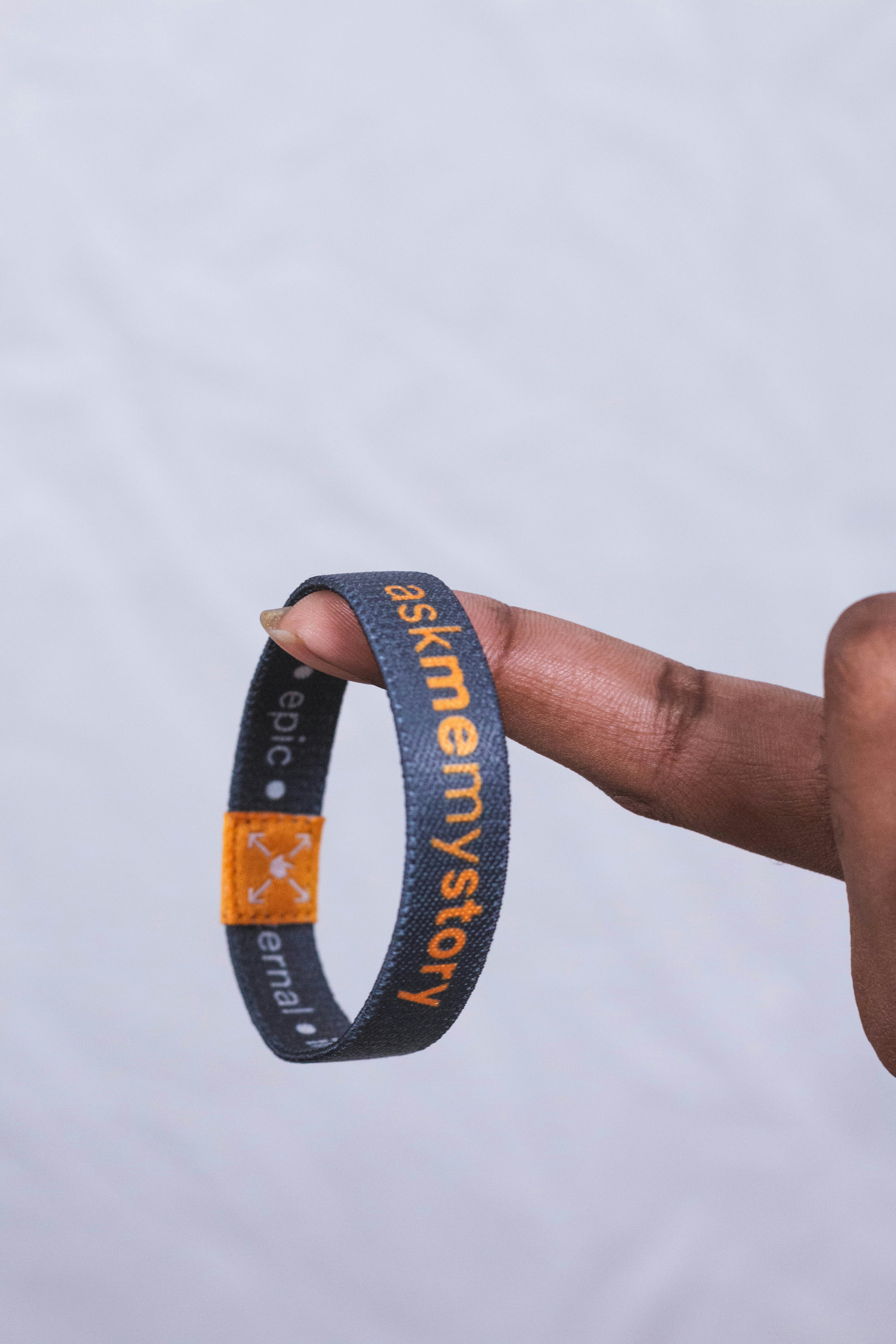 Ask Me Anything Loop: a navy fabric wristband framed by a lone fingertip