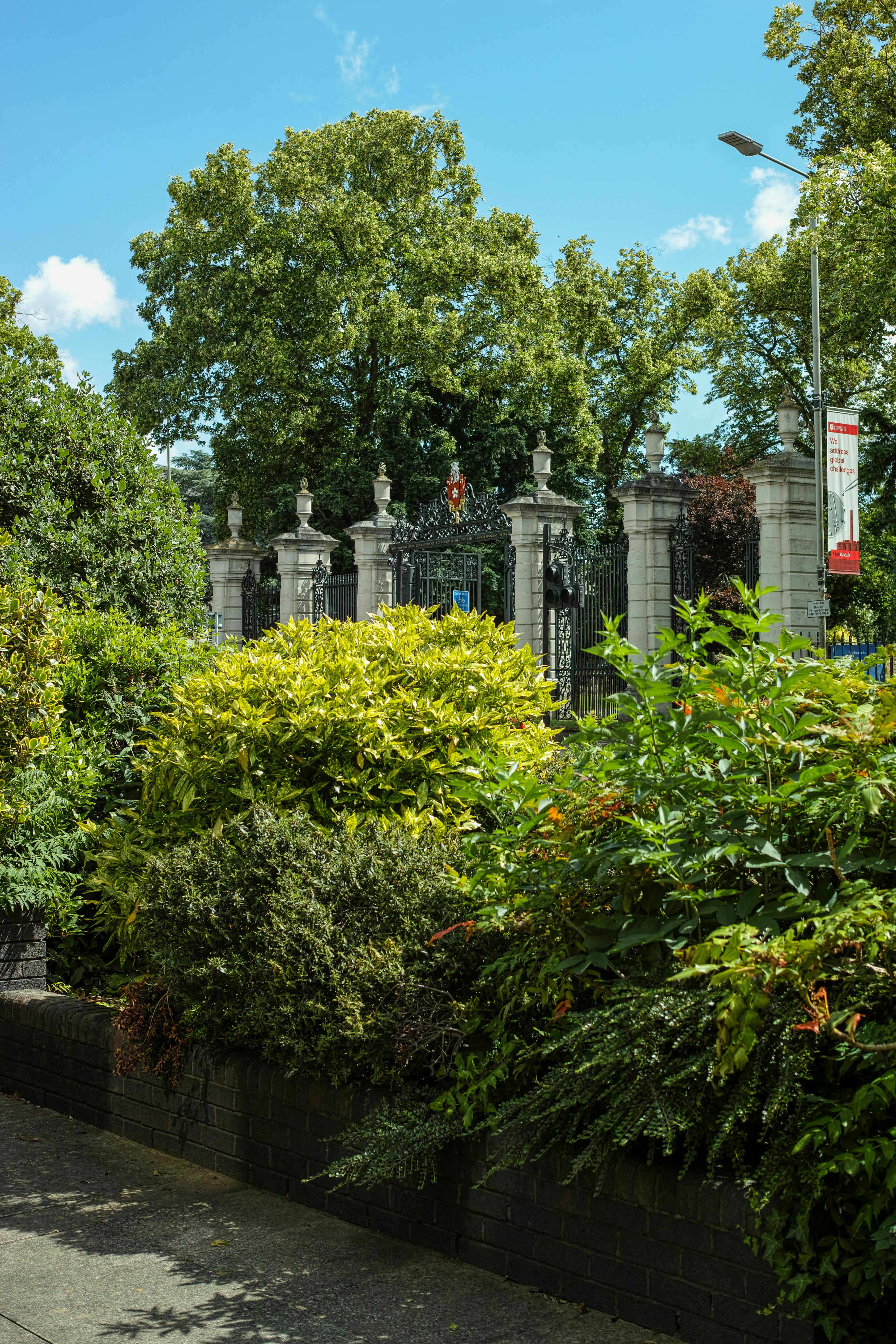 Intricate wrought iron gates framed by vibrant greenery, inviting exploration into a serene urban space.