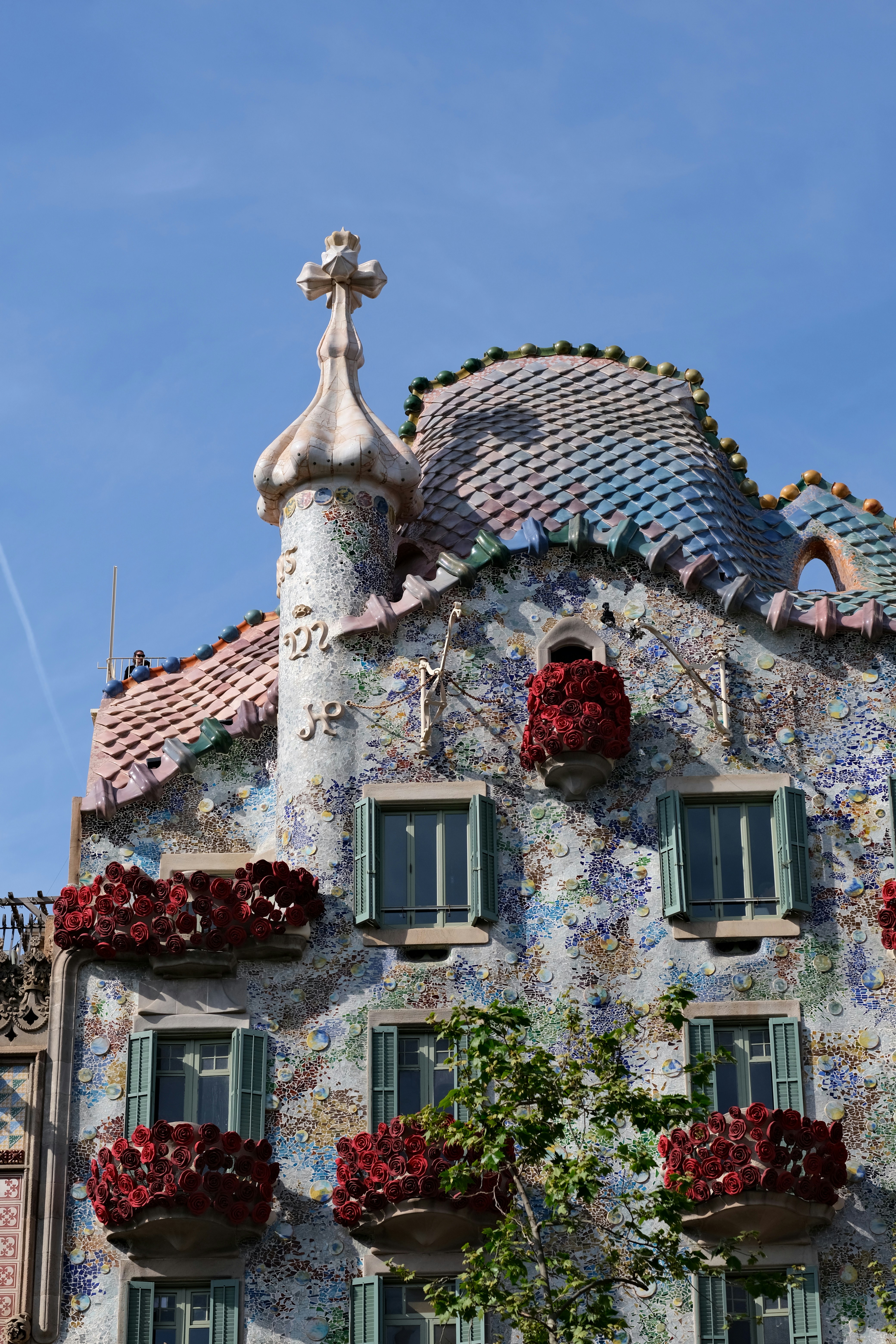 Crimson Roses on Gaudí Mosaic Facade Under a Clear Barcelona Sky