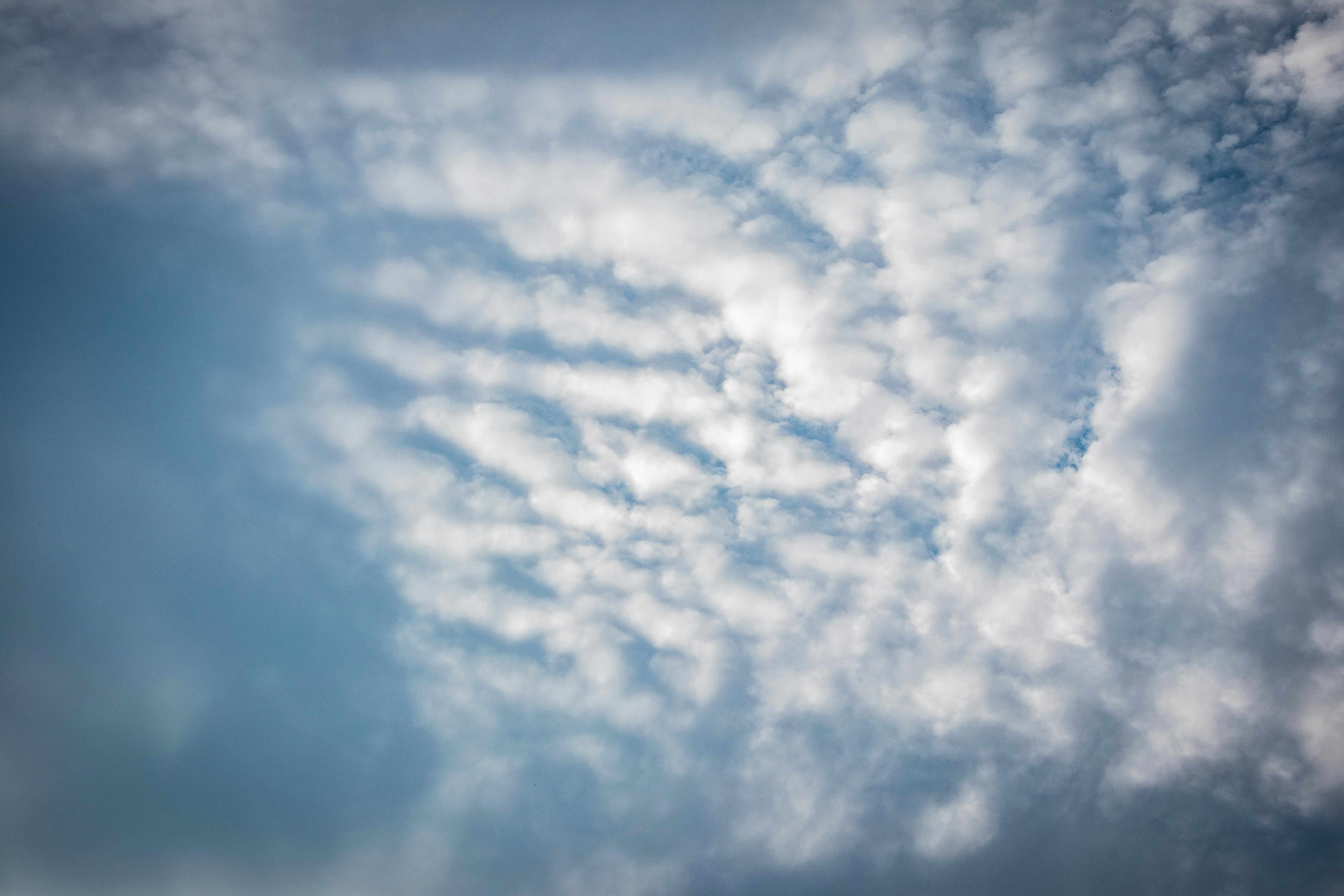 Textured clouds weave a tapestry across the blue sky, creating a serene atmosphere. The interplay of light and shadow adds depth to the scene.